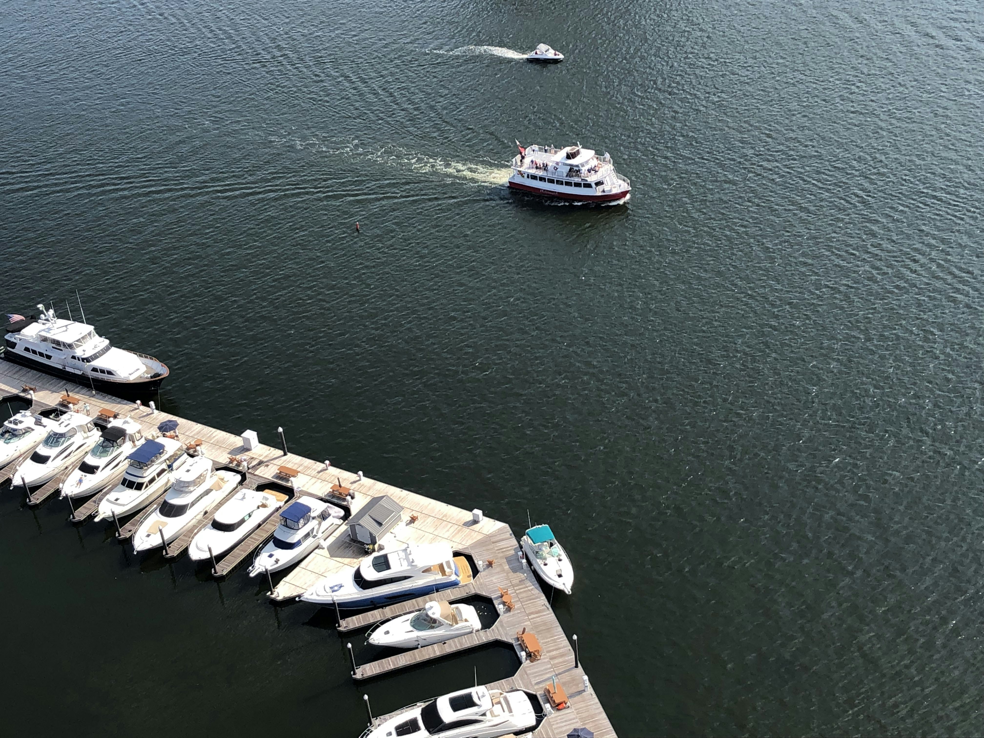 Aerial view of a marina with a docked fleet and two boats navigating open waters.