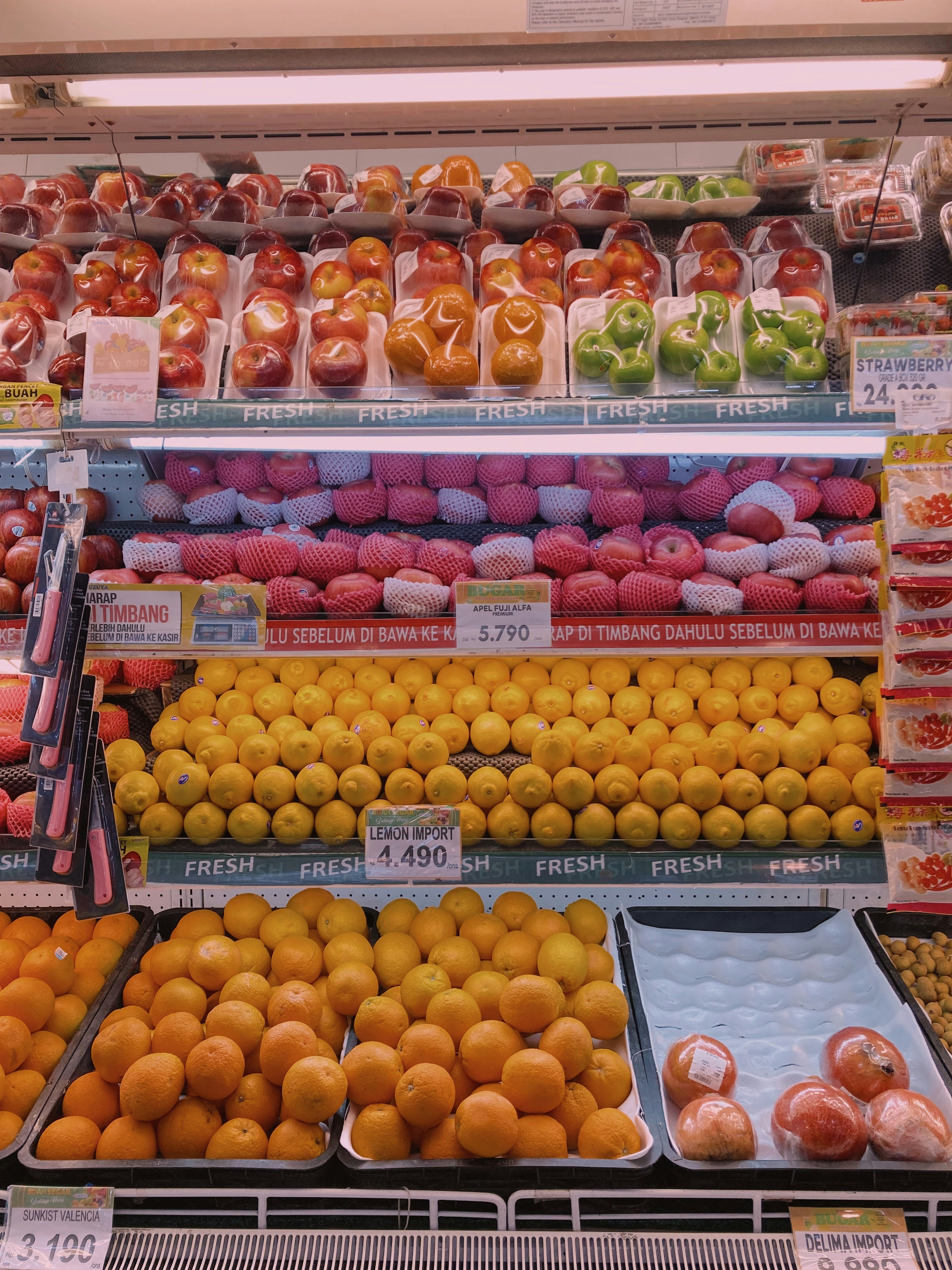 Colorful arrangement of various fruits, including oranges, apples, and lemons, in a market setting. Bright hues highlight the freshness of the produce.