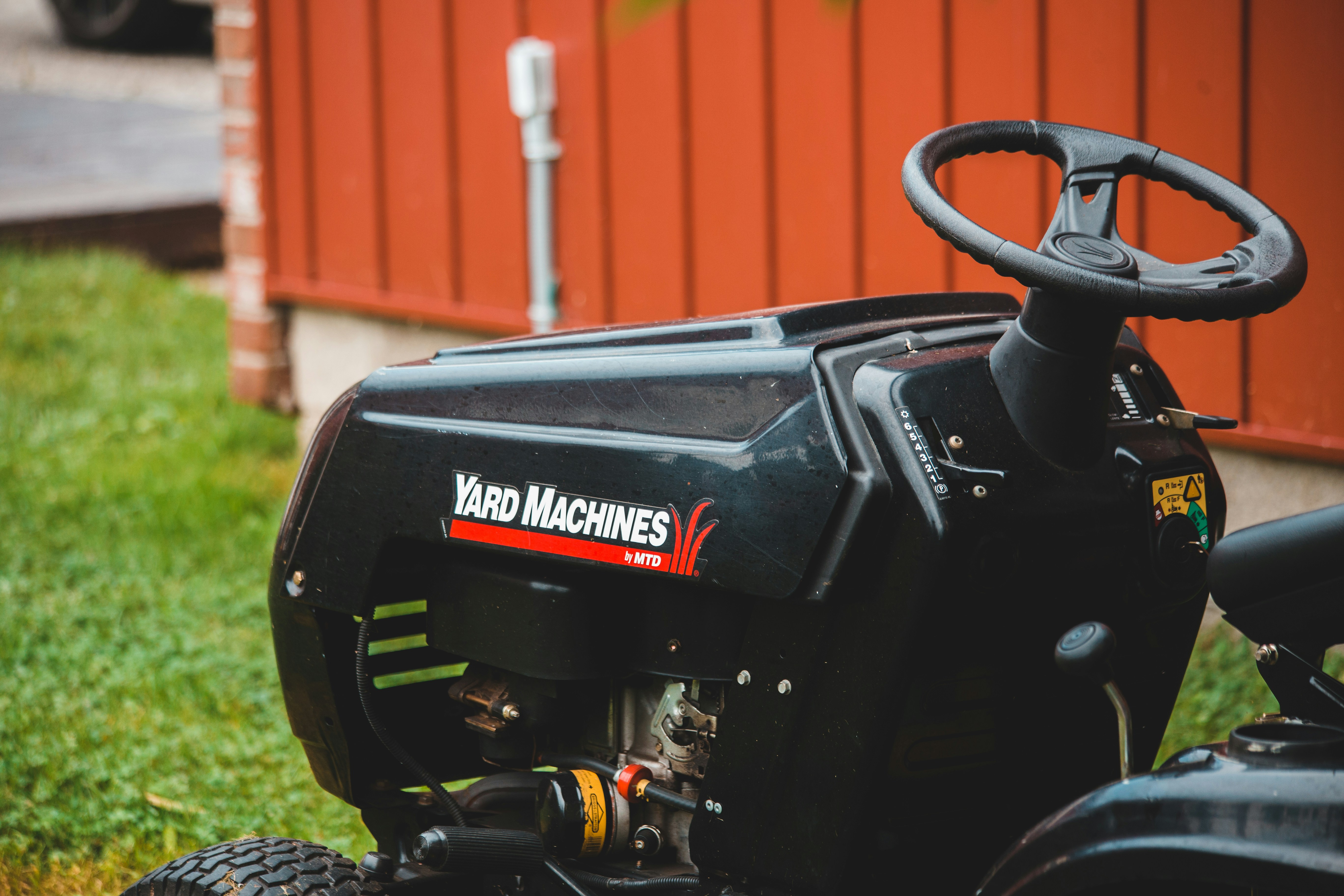Yard Machines Lawn Tractor Resting Beside a Crimson Fence