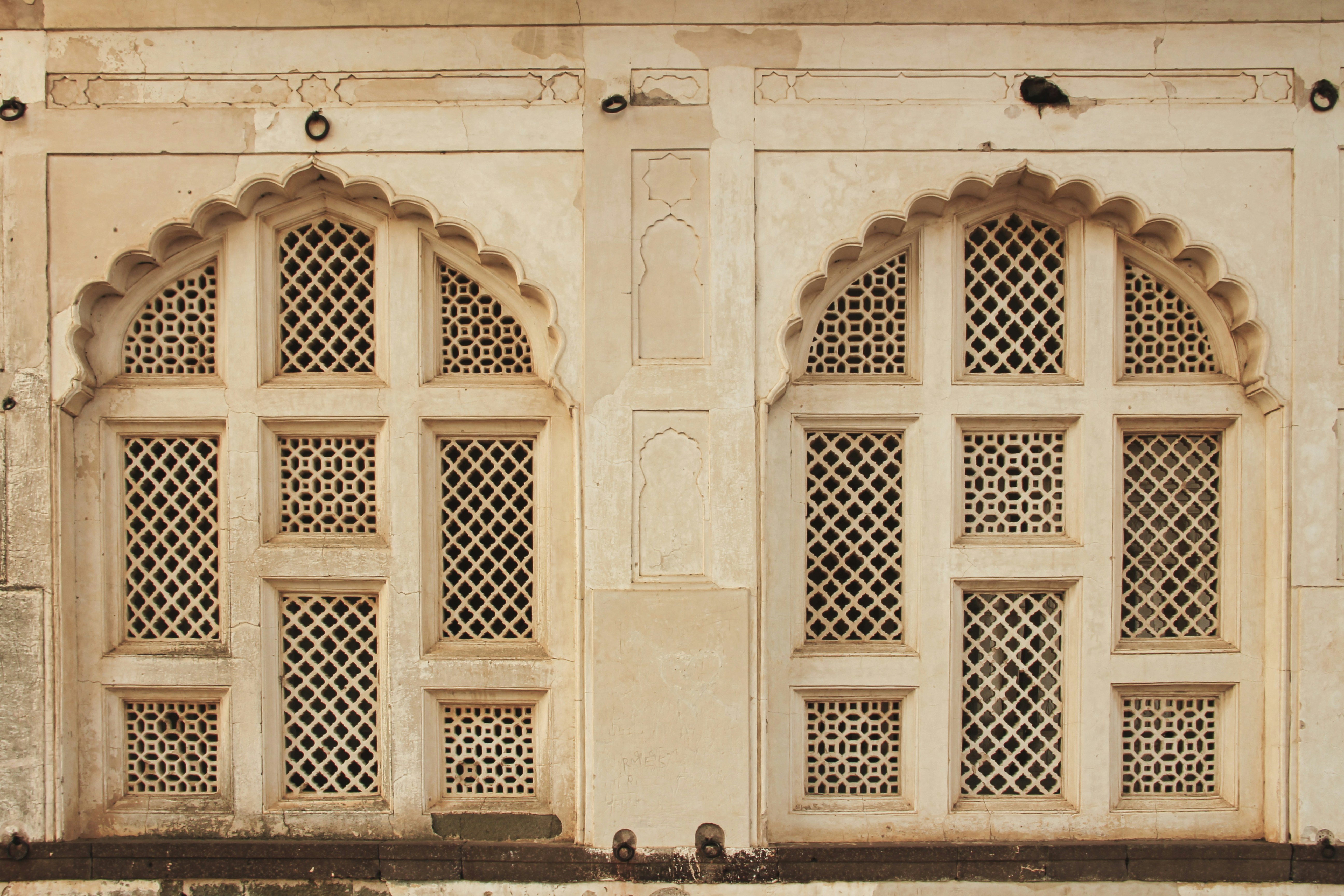 Ornately carved jaali windows with symmetrical patterns at Bibi Ka Maqbara.