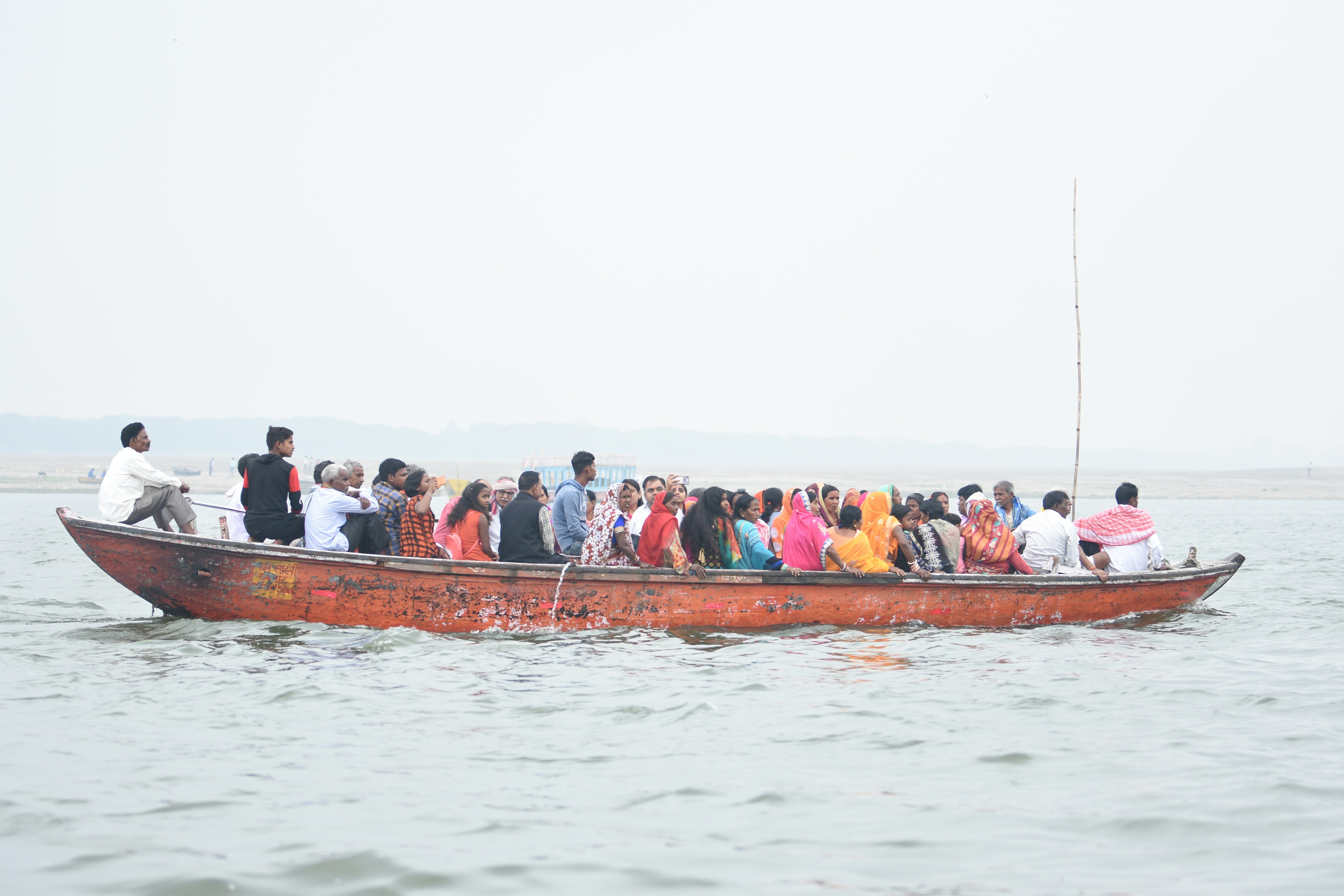 Color on the Tide: A Crowded Wooden Boat Crossing a Pale Estuary