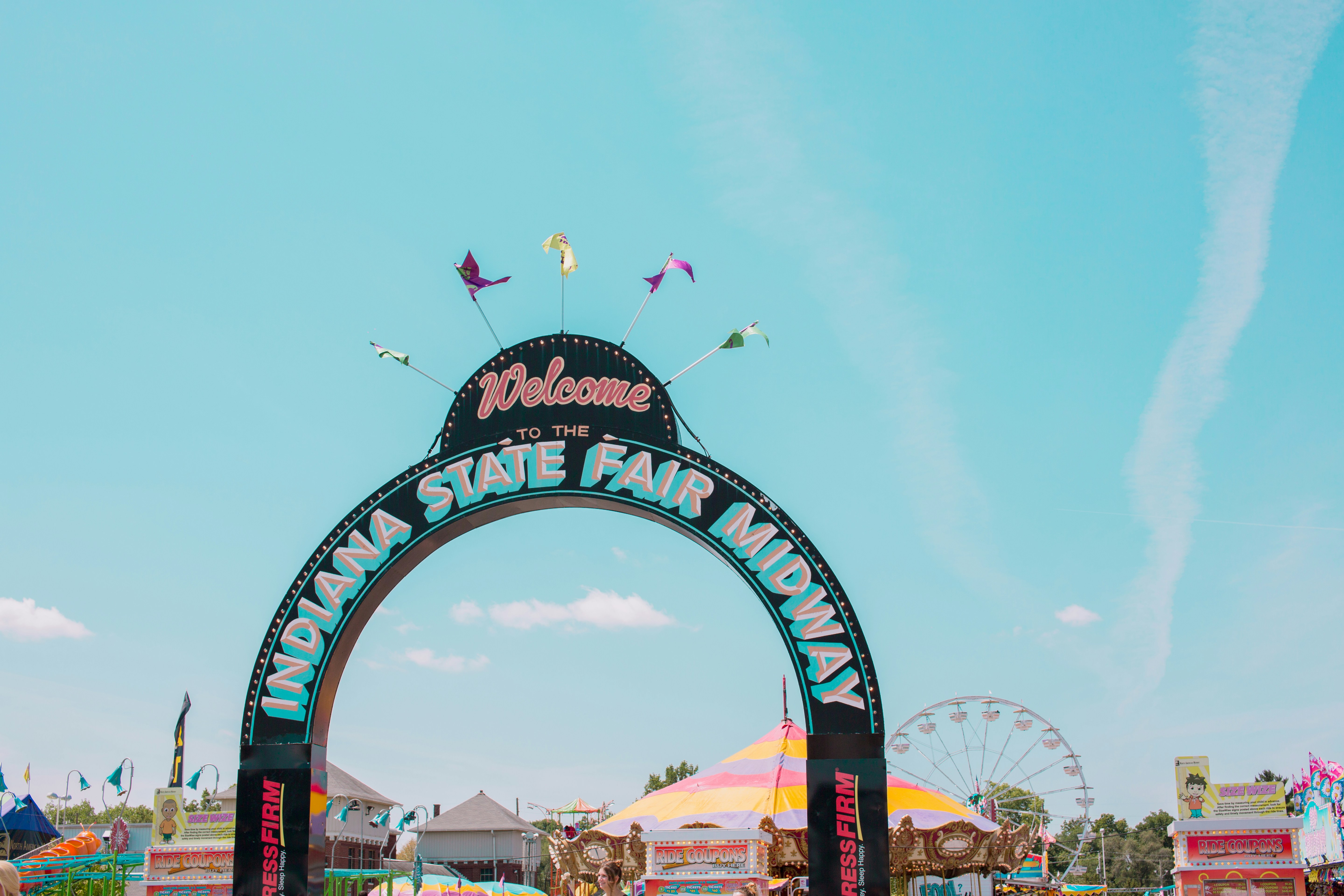 Gateway Arch at the Indiana State Fair Midway: Flags, Sky, and a Distant Ferris Wheel