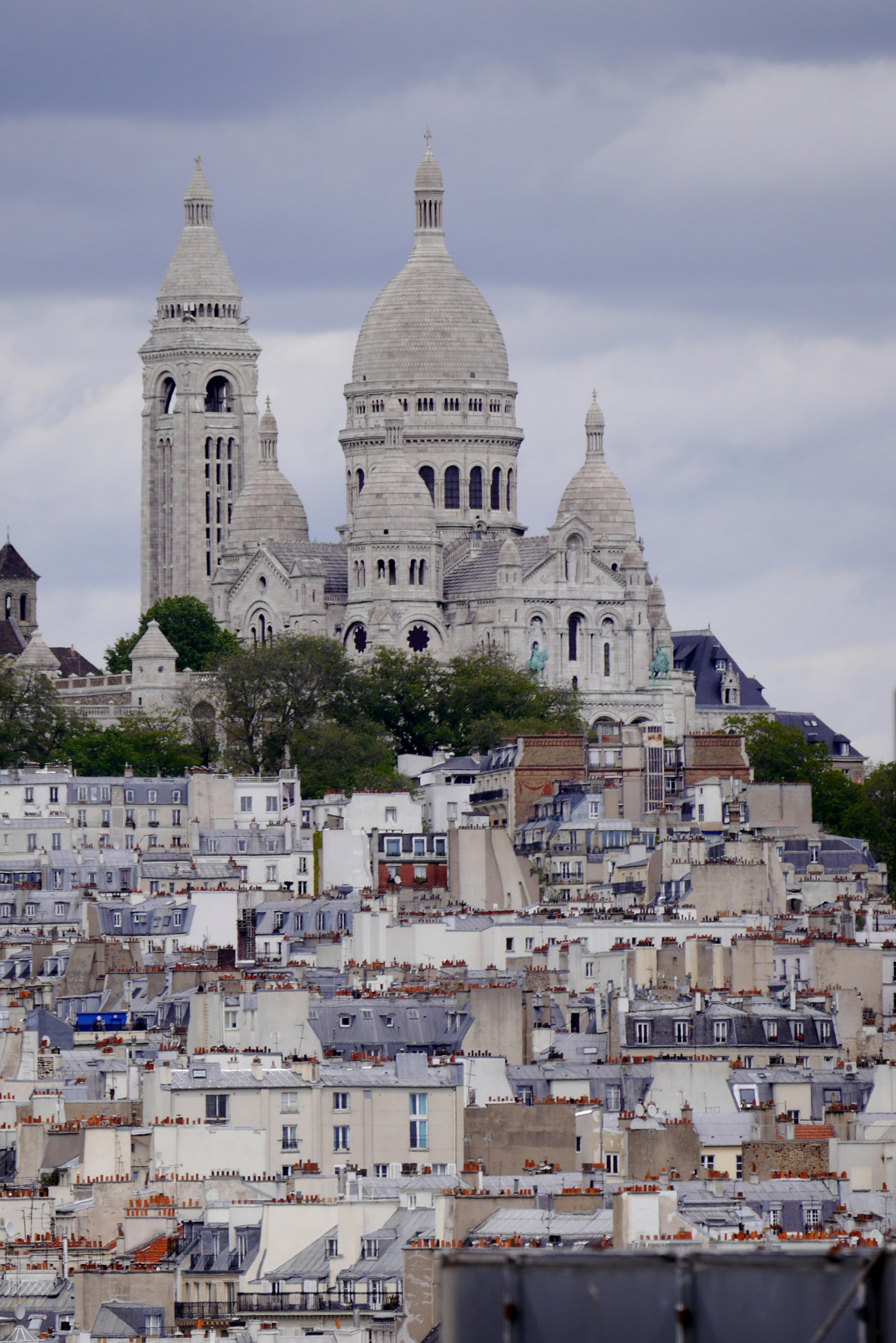 Sacré-Cœur Basilica perched atop the Montmartre hill, surrounded by a tapestry of Parisian rooftops. A blend of architectural beauty and urban landscape.