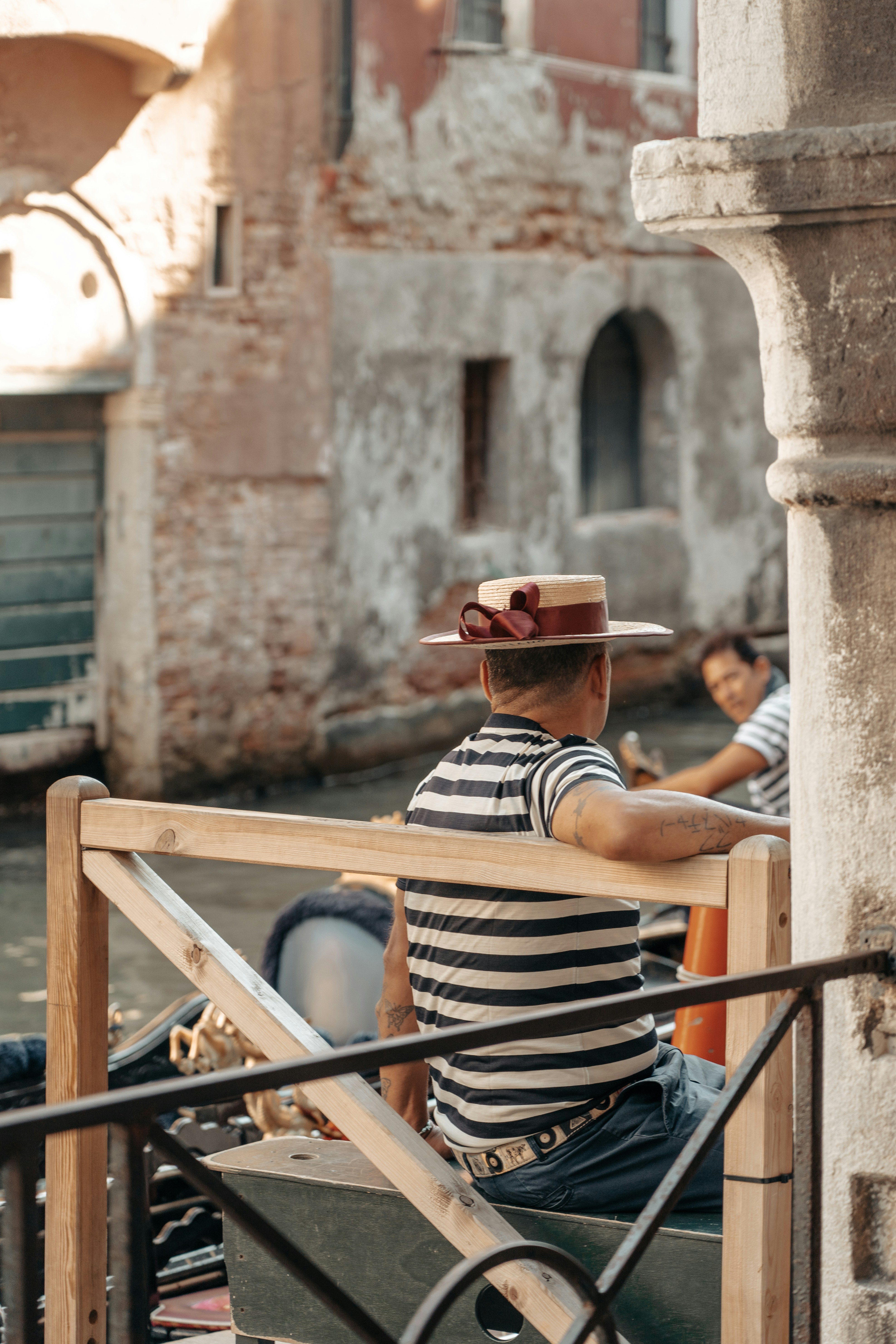 Striped-Top Boater Framed by a Weathered Venetian Canal