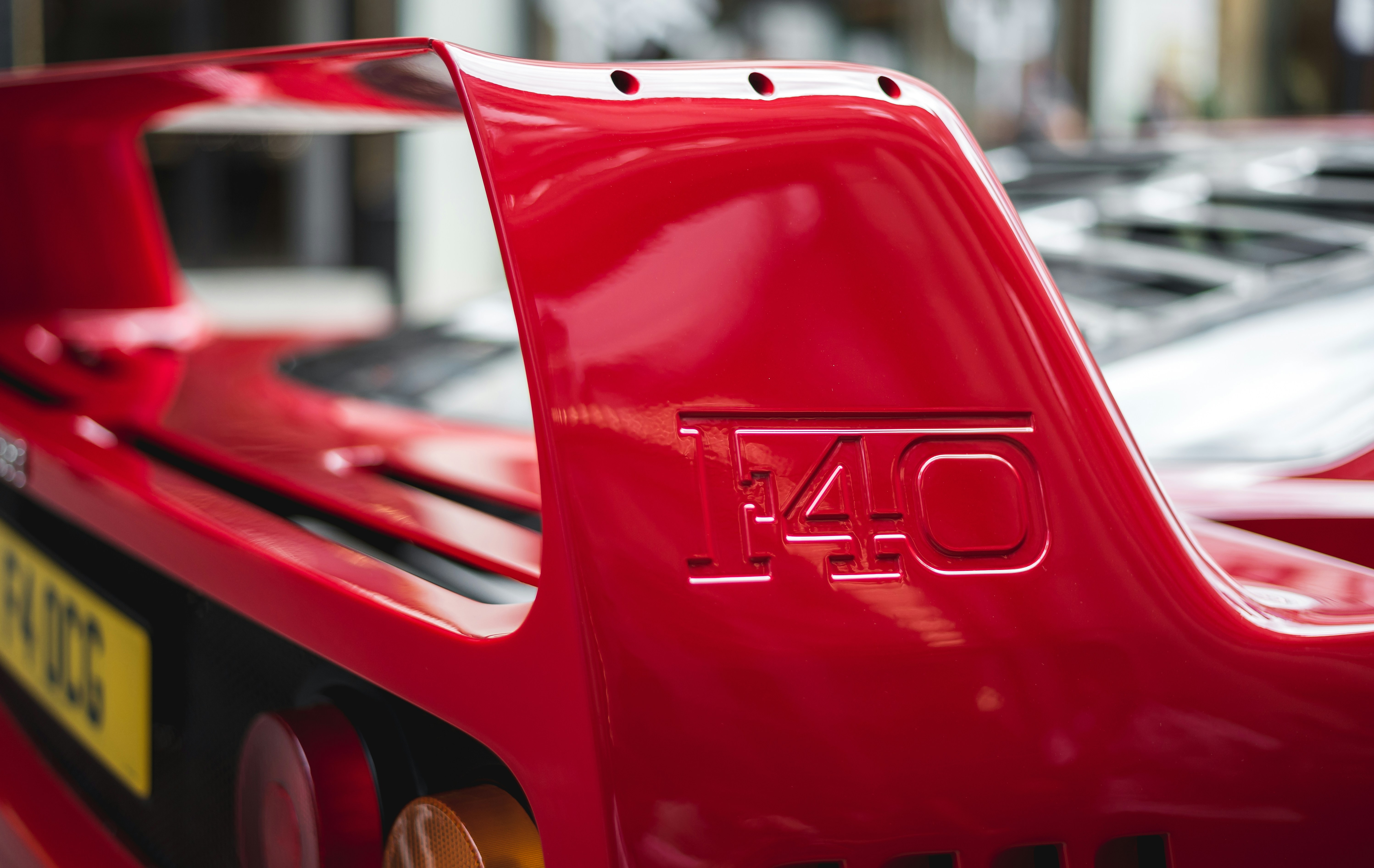 Red Ferrari 140 Wing Highlight: Emblem and Curves in Focus