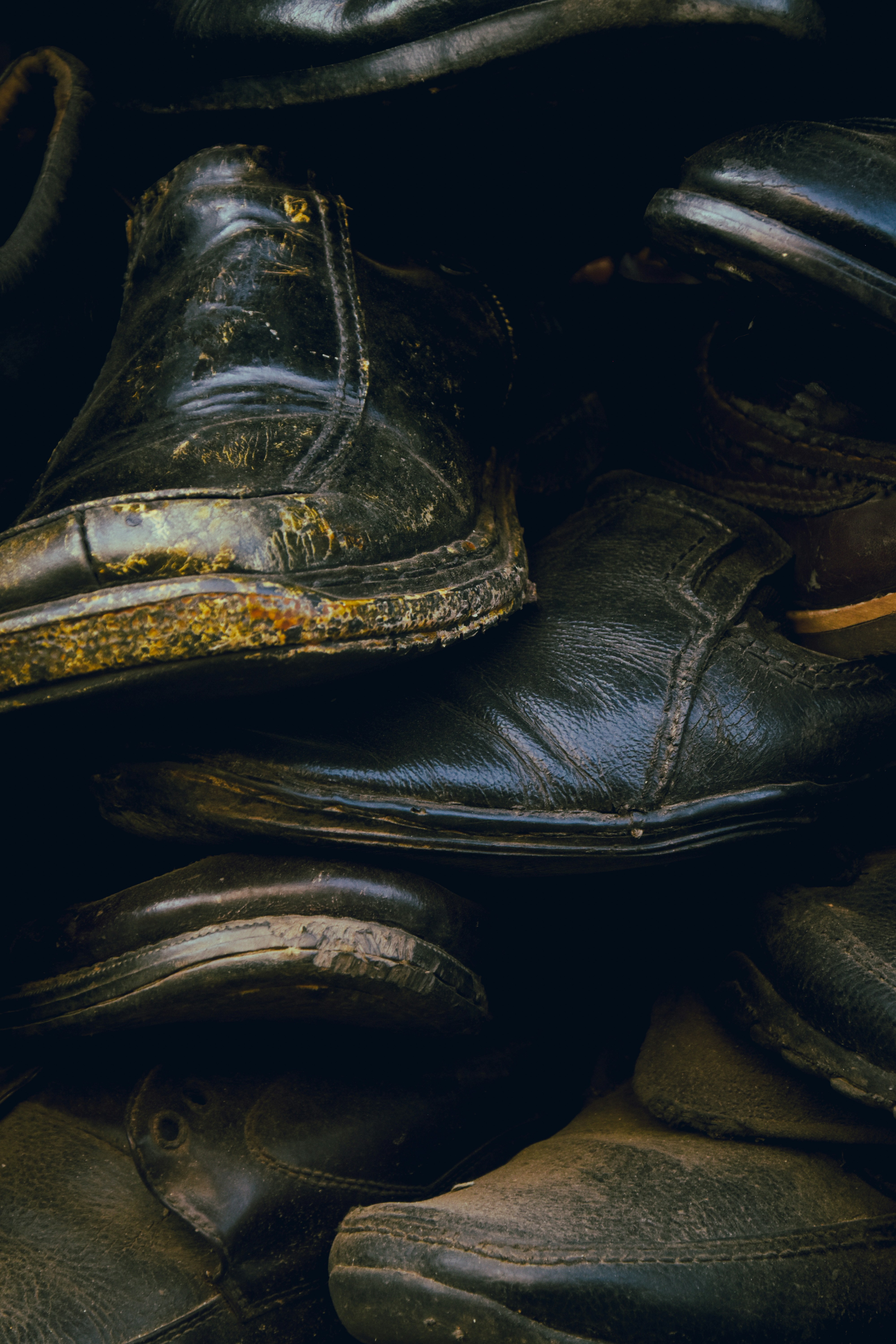 Mud-Stained Boots in Shadow: A Quiet Tangle of Worn Leather