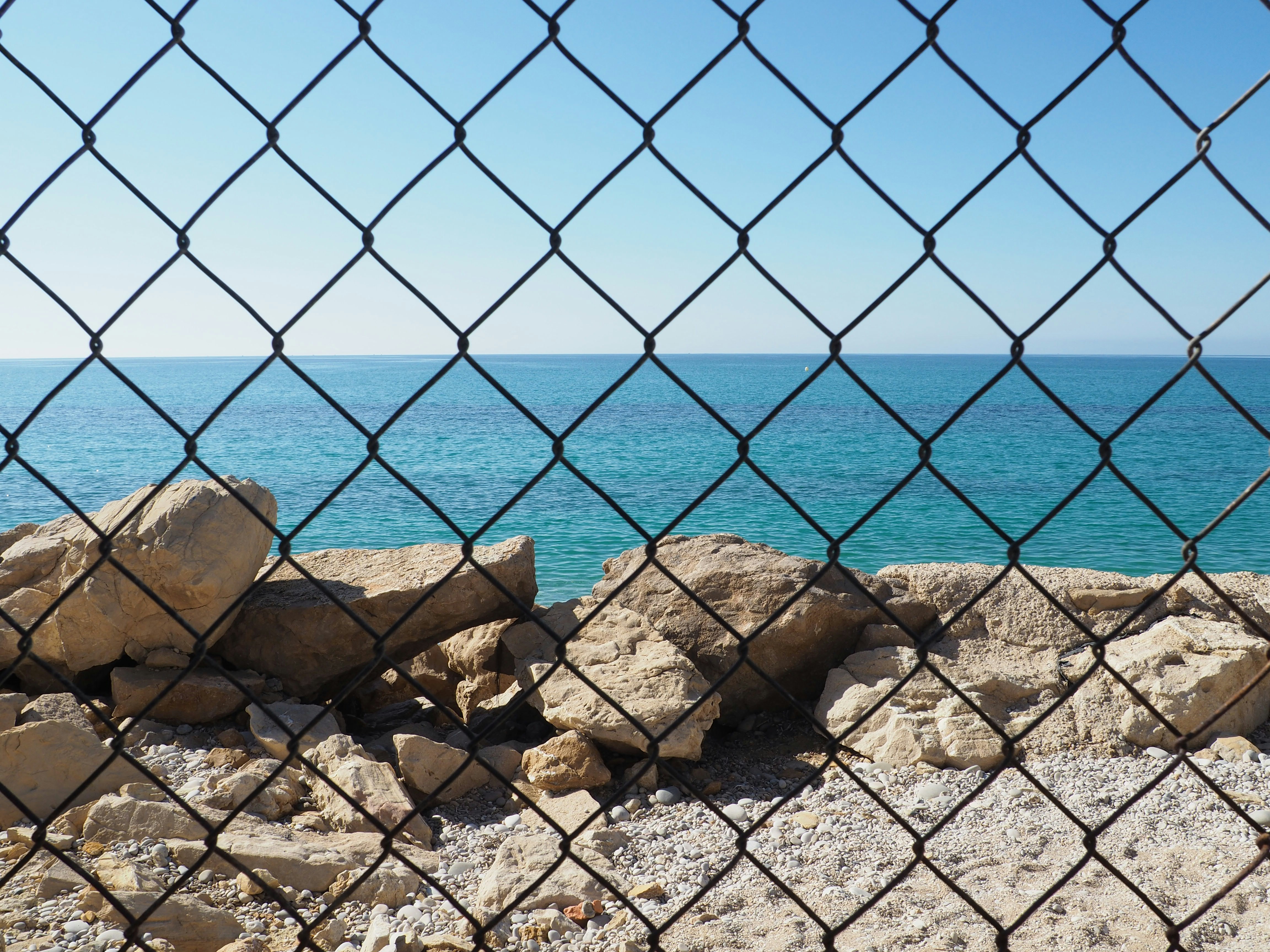 Horizon Through the Chain-Link Mesh: Rocky Seascape