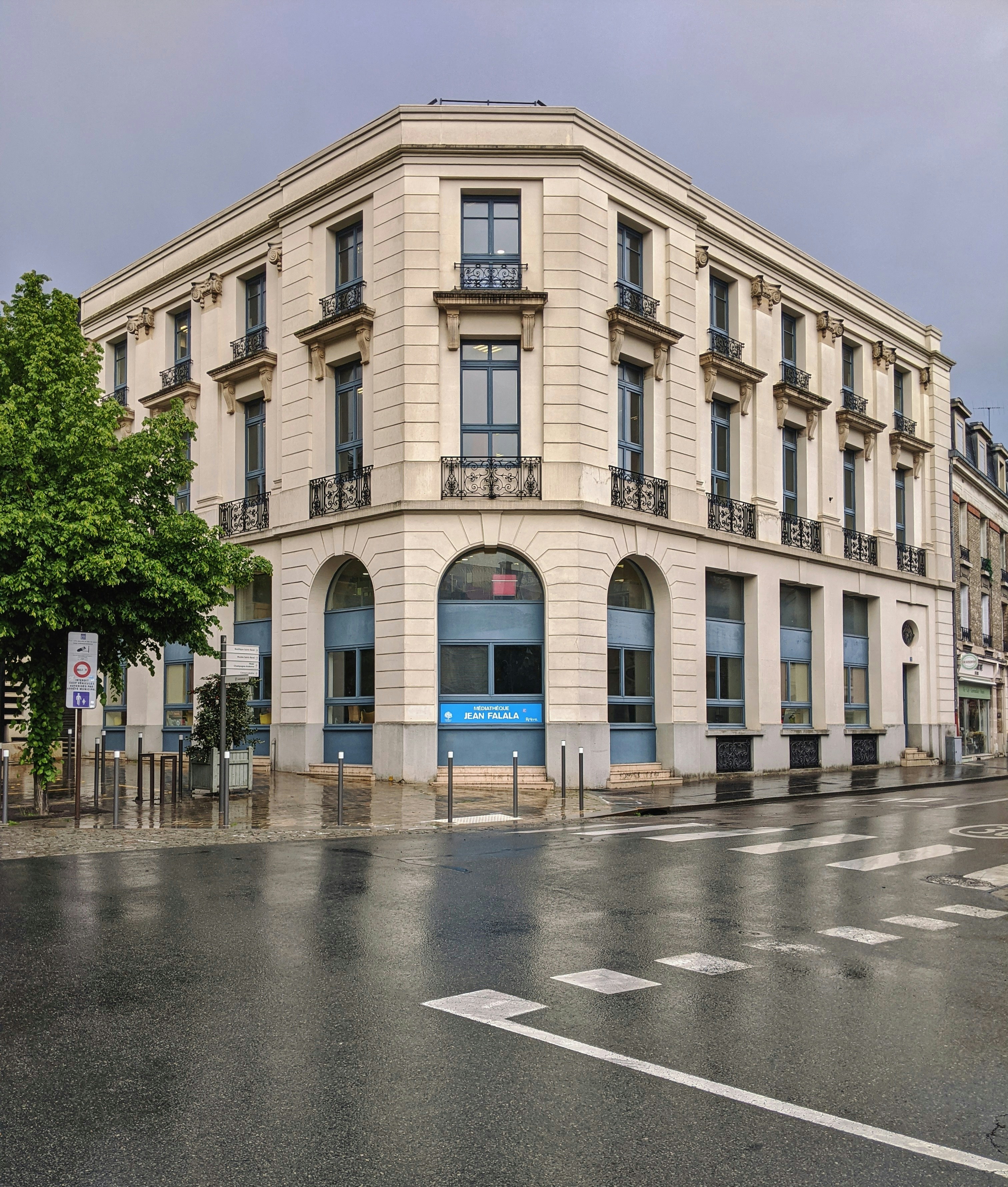 Rain-Kissed Facade: Arched Ground-Floor Windows on a Corner Building