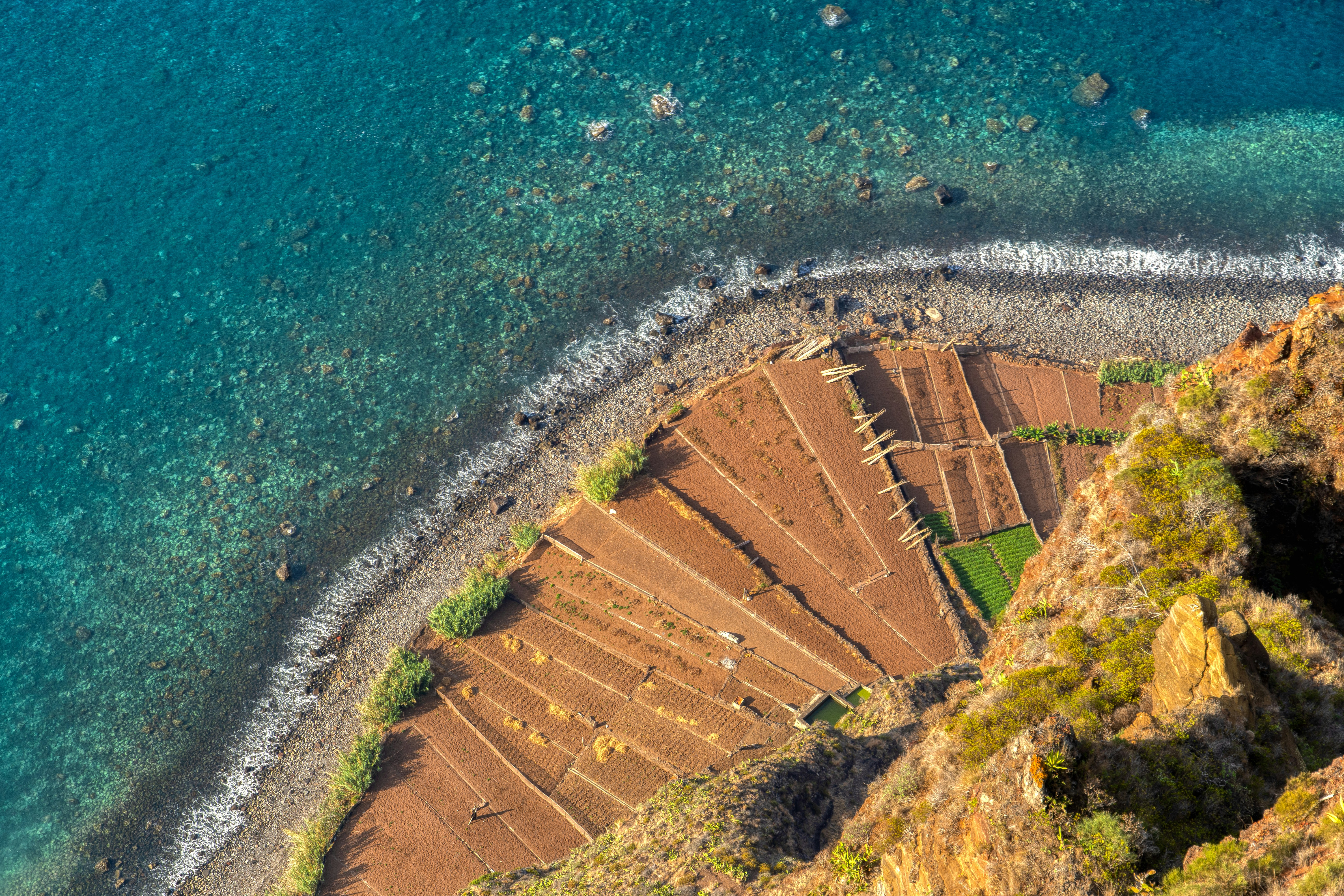 Aerial view of terraced cliffs meeting the turquoise ocean, with waves gently lapping the shore.