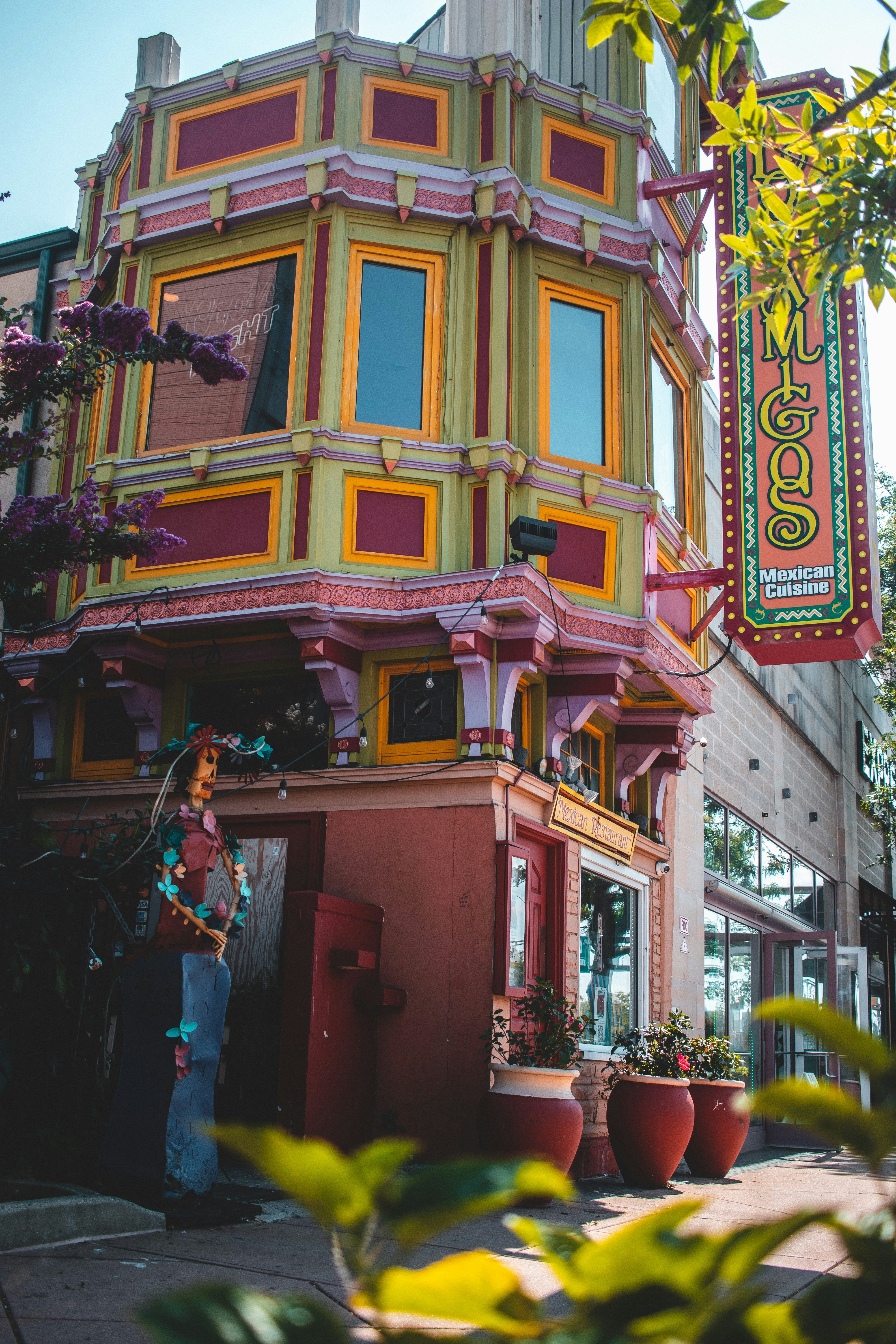 Colorful corner restaurant showcasing unique architecture and decorative elements, enhanced by surrounding greenery.