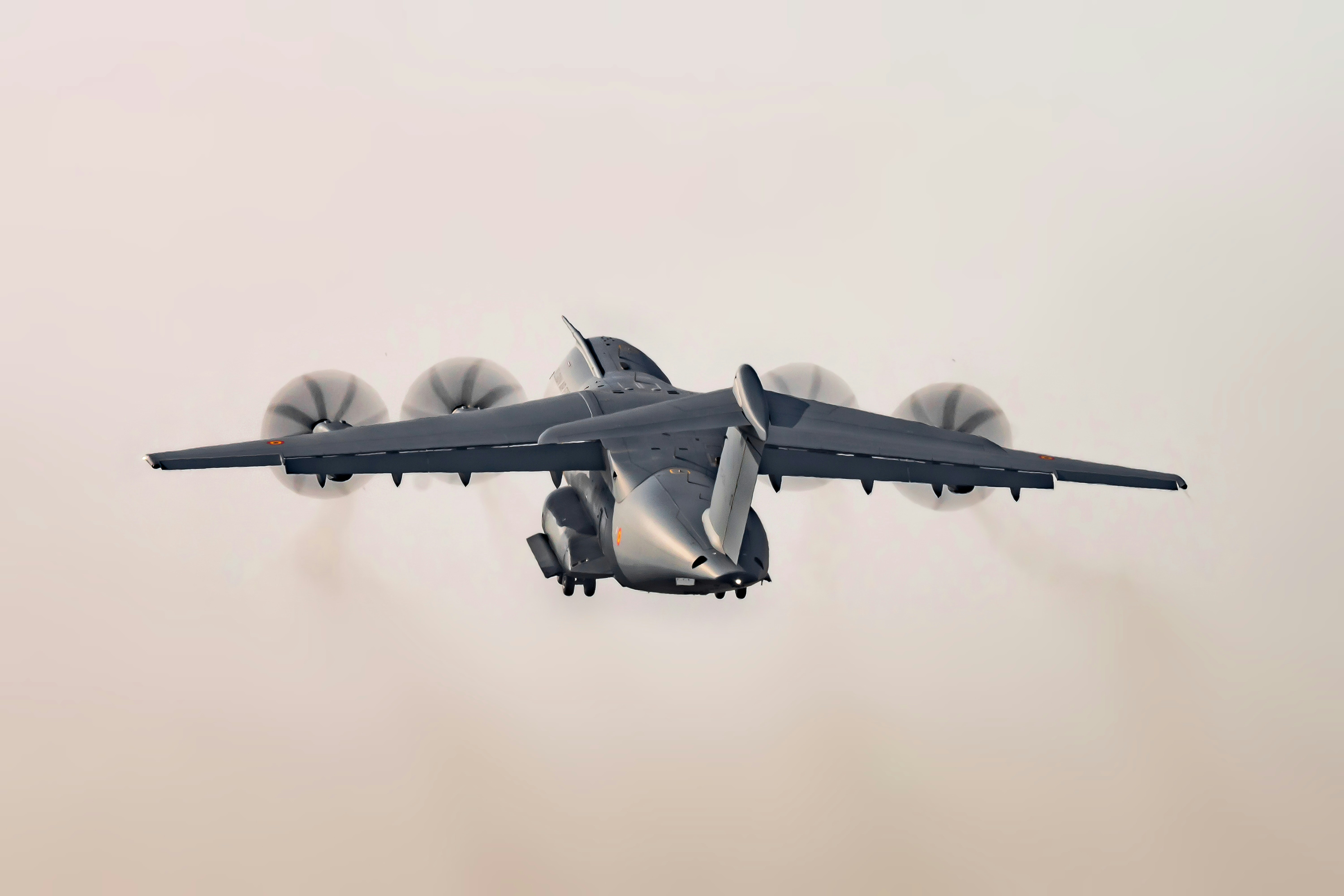 Military transport aircraft taking off against a soft, pastel sky.