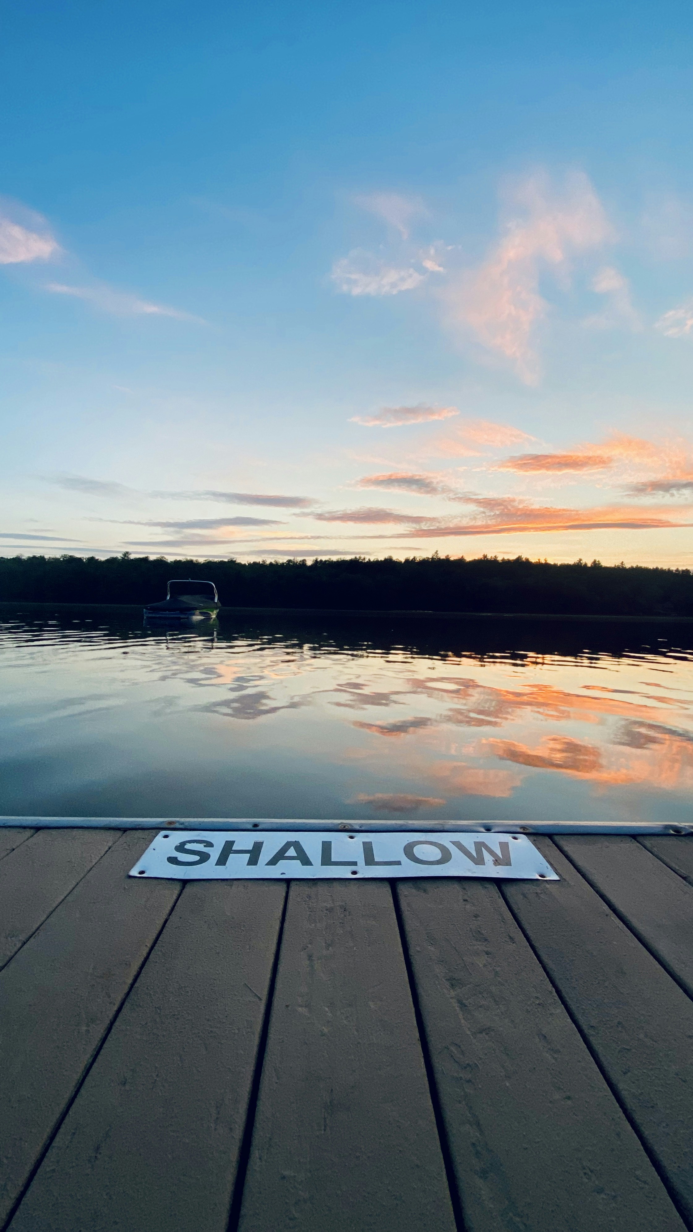 Sunset on Silent Water: A Dockside Sign Beneath a Sky of Reflected Hues