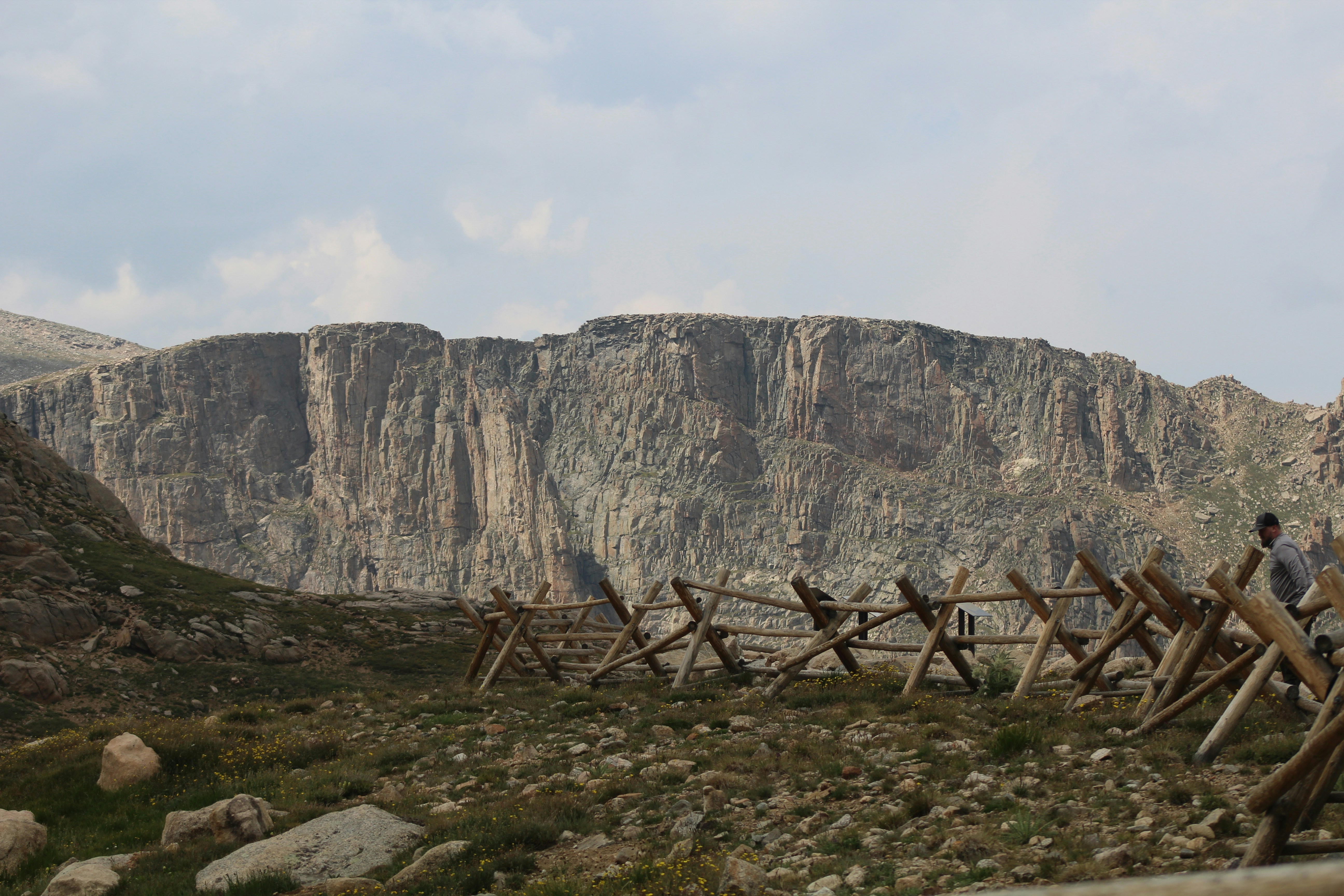 brown wooden fence on green grass field near gray rocky mountain during daytime