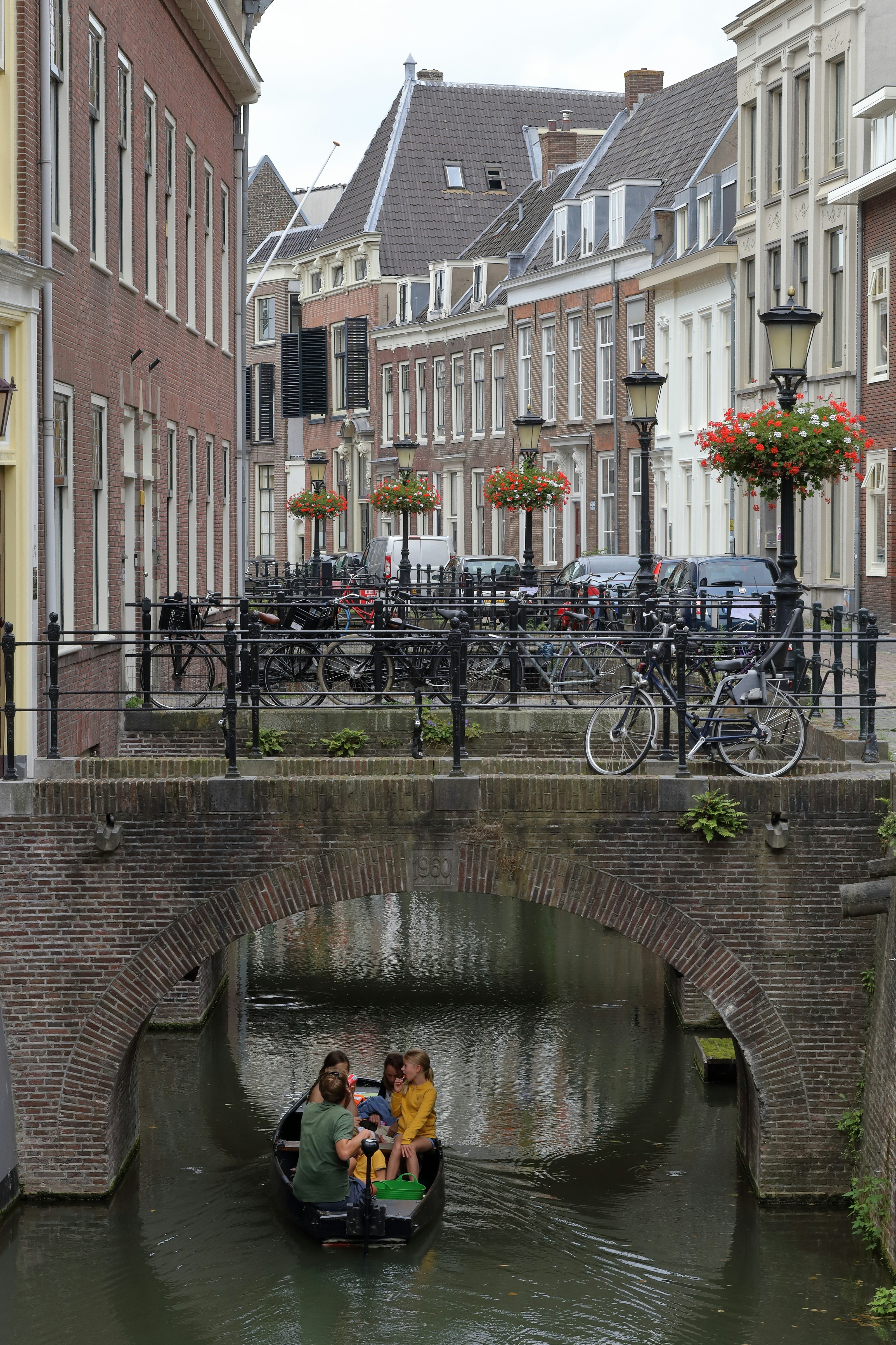 Canal Reverie: A Family Boat Glides Beneath a Brick-Arch Bridge Lined with Bicycles
