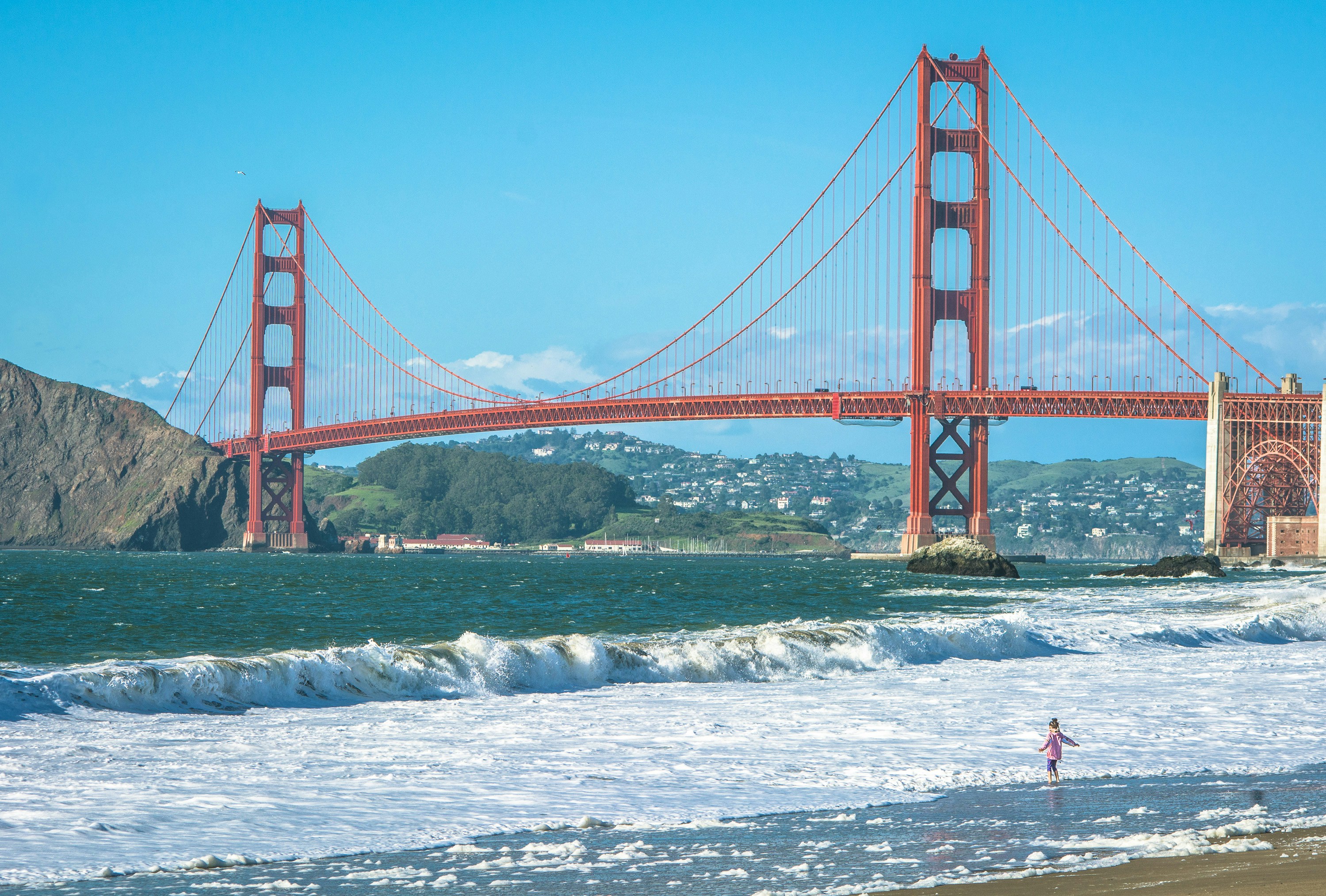 Crimson Towers Over the Coastal Wake: Golden Gate Bridge from a Sunlit Beach