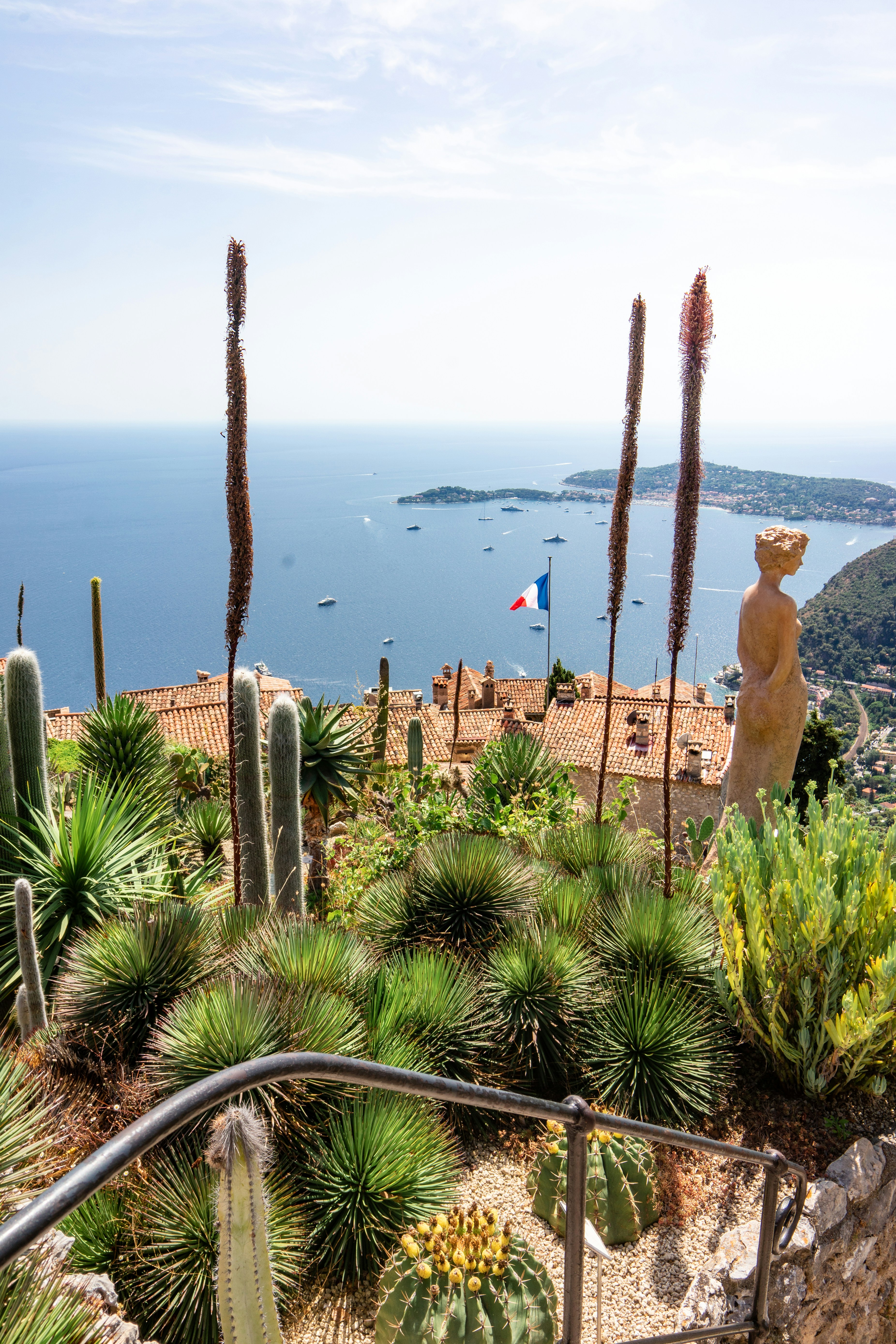 Cacti and succulents overlook terracotta rooftops and the azure Mediterranean Sea in Eze, France.