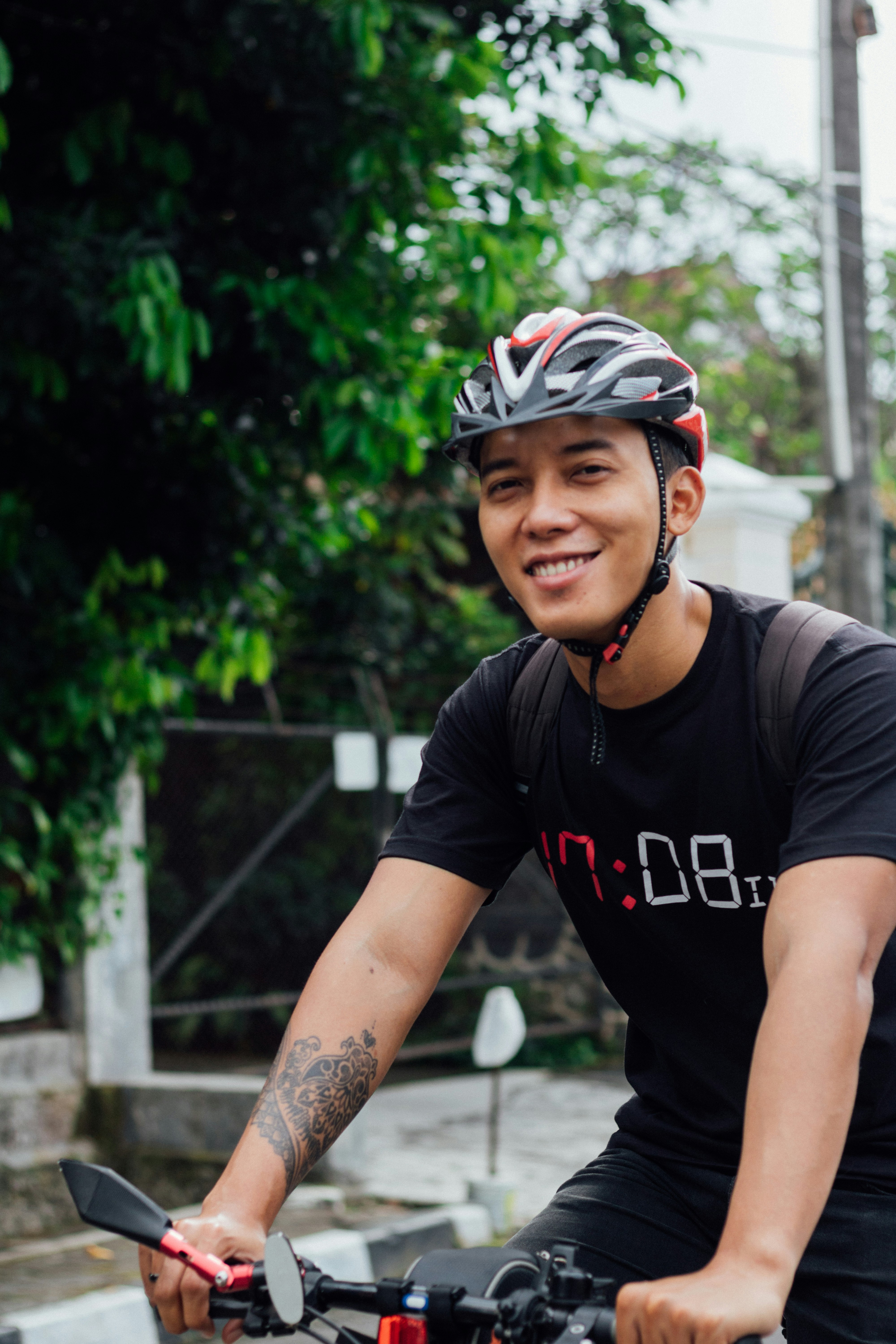 Cyclist smiling while riding through a lush green neighborhood, showcasing a sense of freedom and adventure.