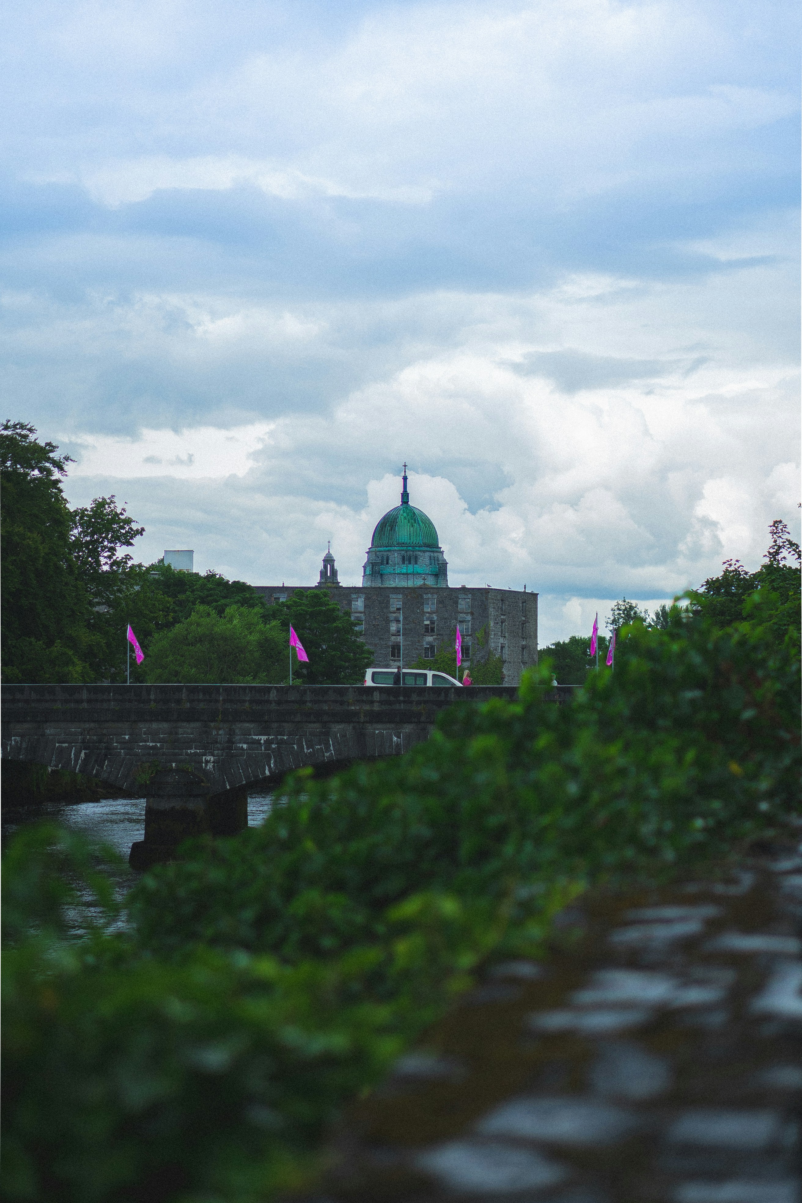 Emerald Dome Over the River: Pink Pennants on a Quiet Stone Bridge