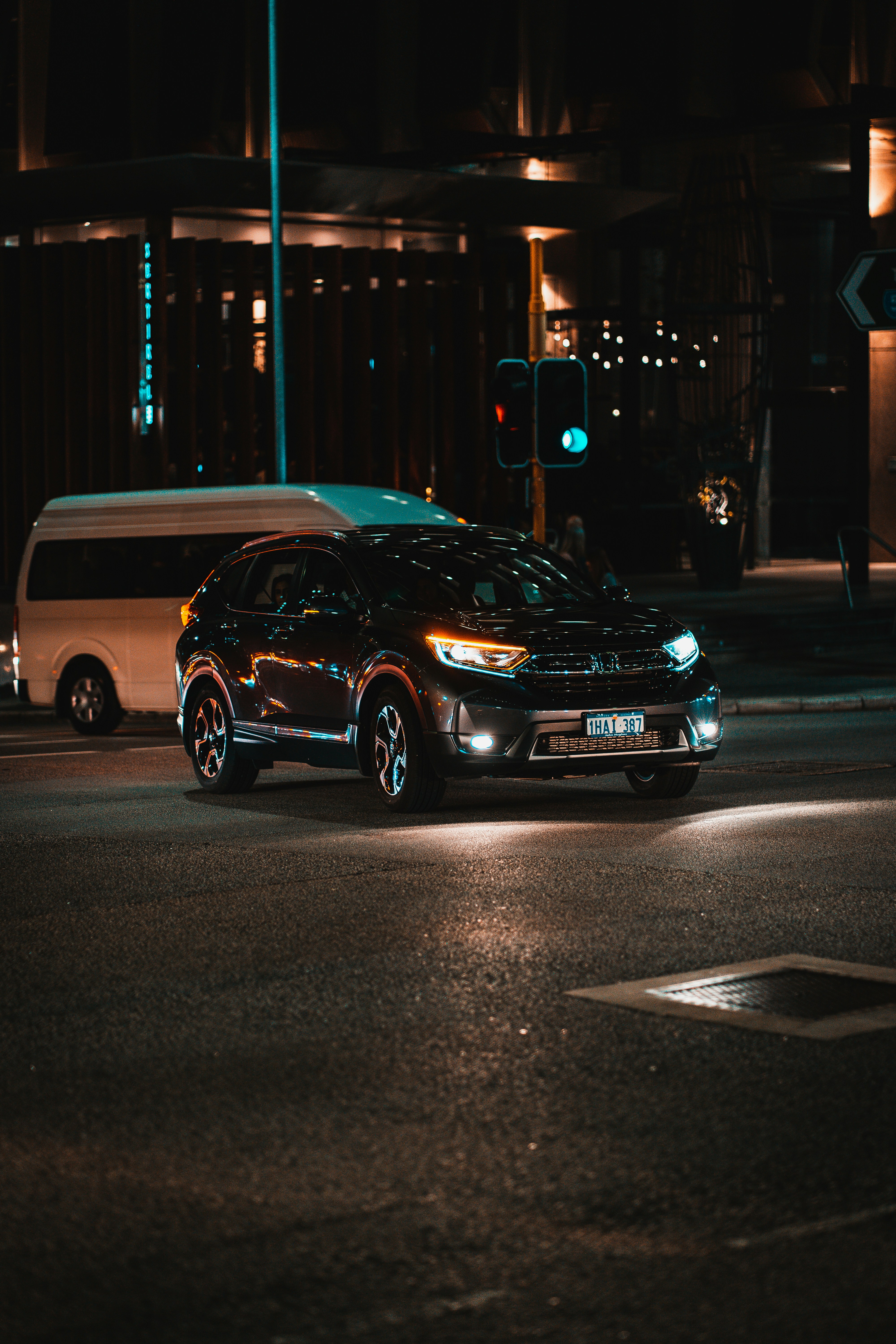 A sleek SUV navigating a city intersection illuminated by streetlights and traffic signals at night.
