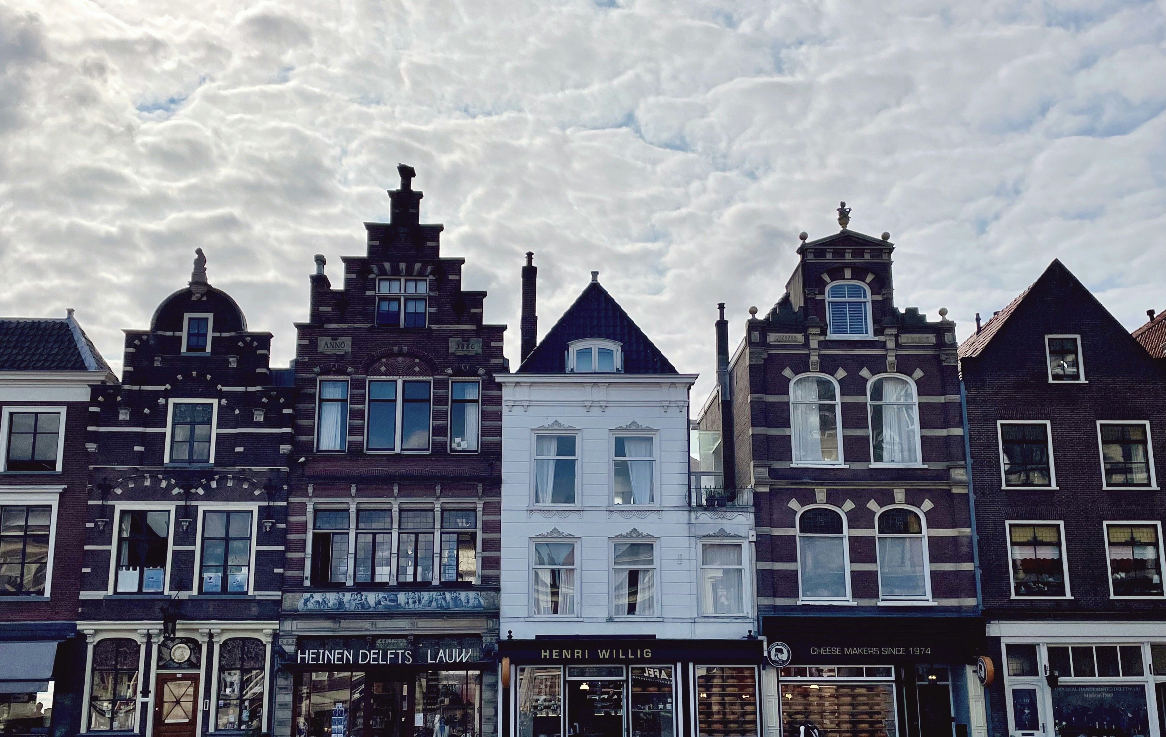Ornate brick and stone facades of historic buildings under a textured cloud-filled sky.