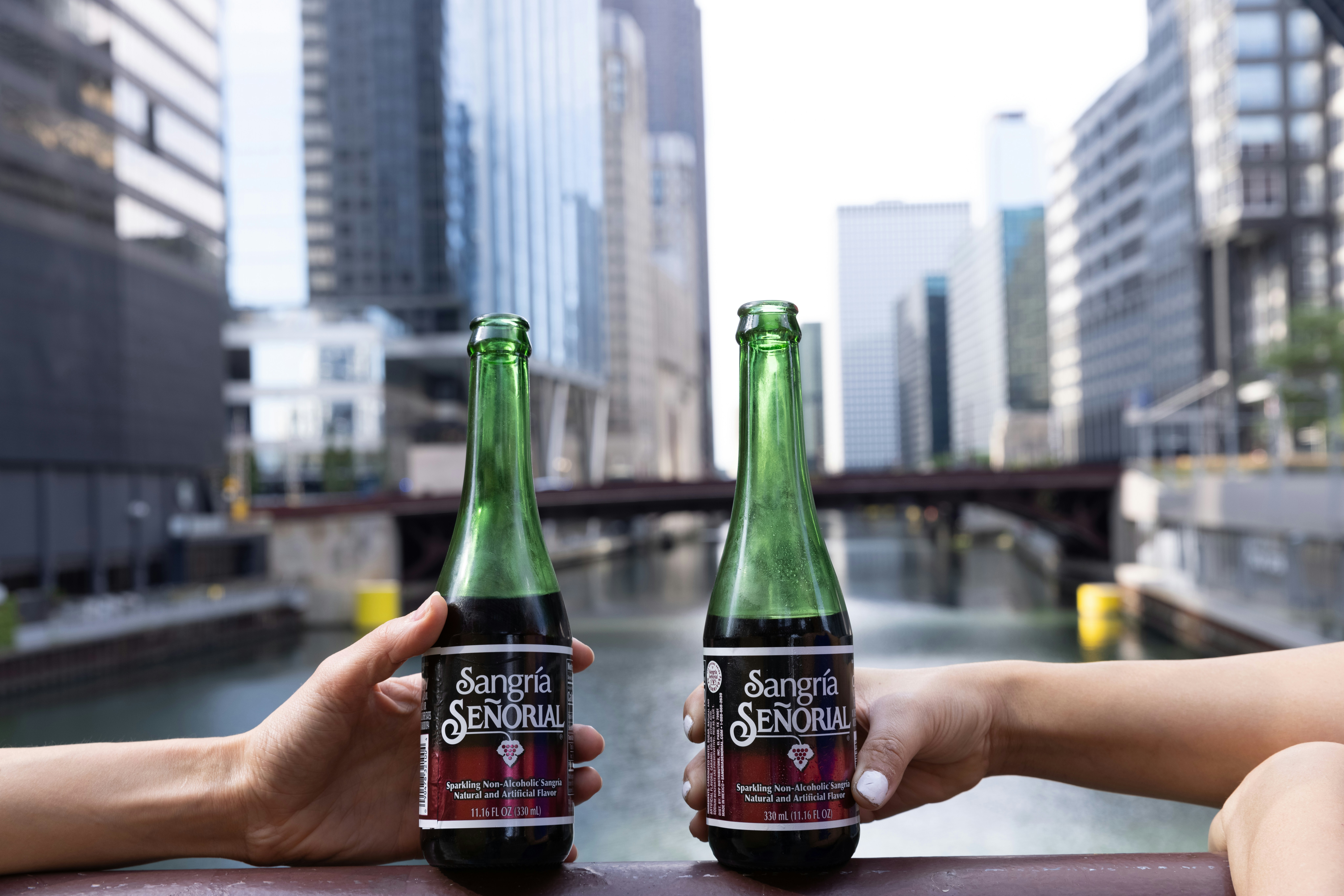 City Toast: Twin Sangria Bottles Anchoring a Riverfront Skyline