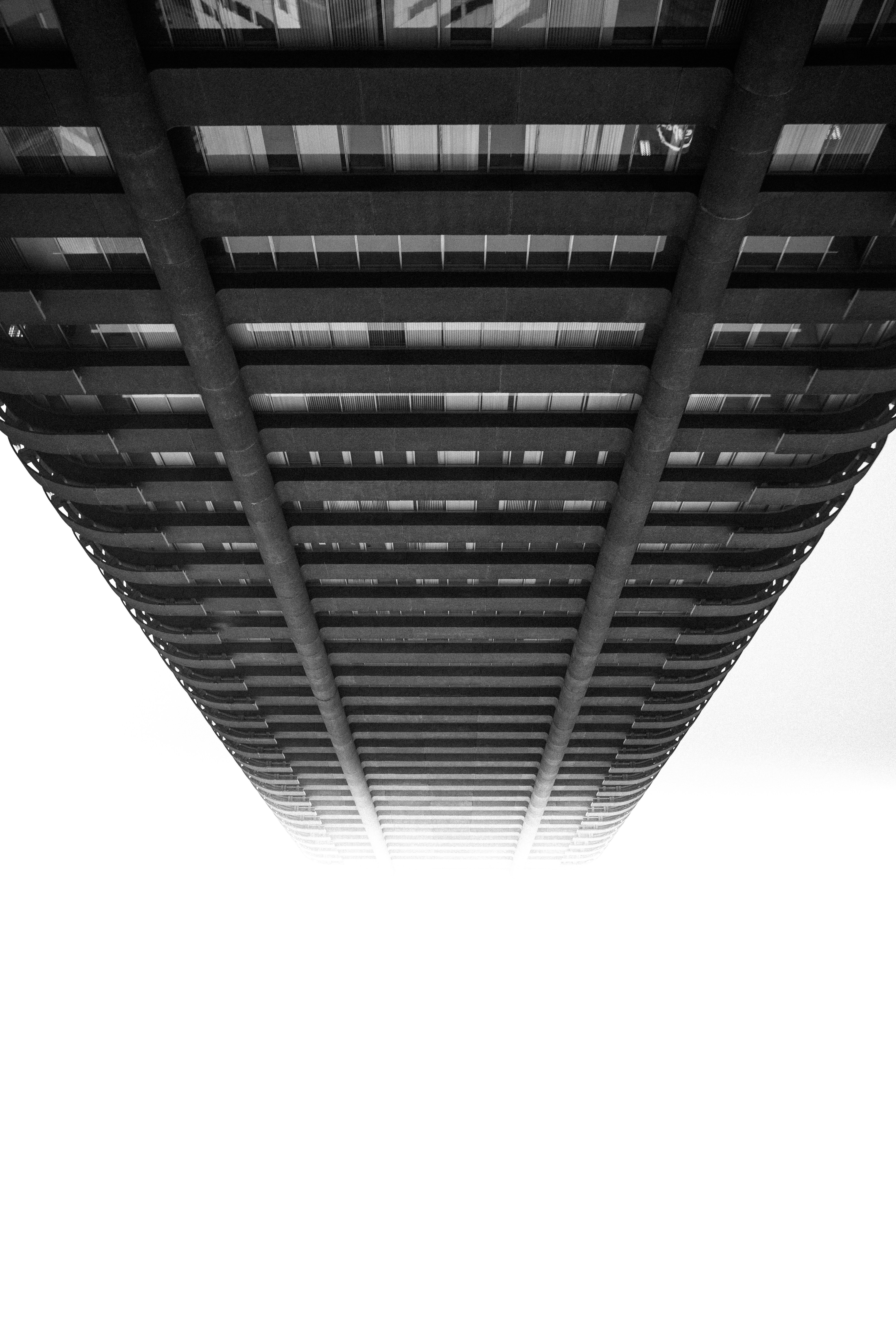 Abstract view of a building's underside showcasing structural lines and patterns in monochrome. The composition emphasizes symmetry and depth.