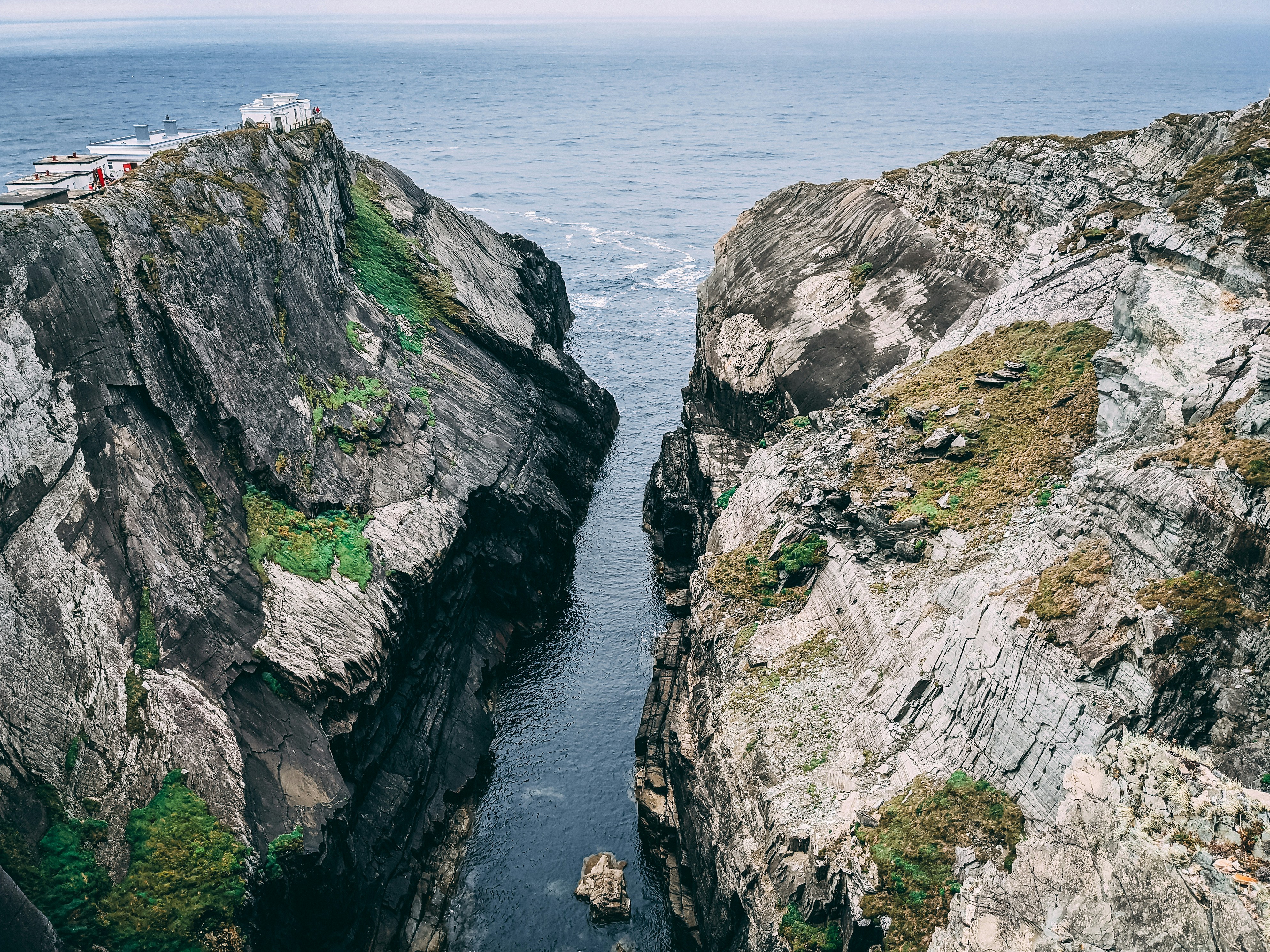 Narrow sea inlet framed by steep, rocky cliffs at Mizen Head, Ireland.