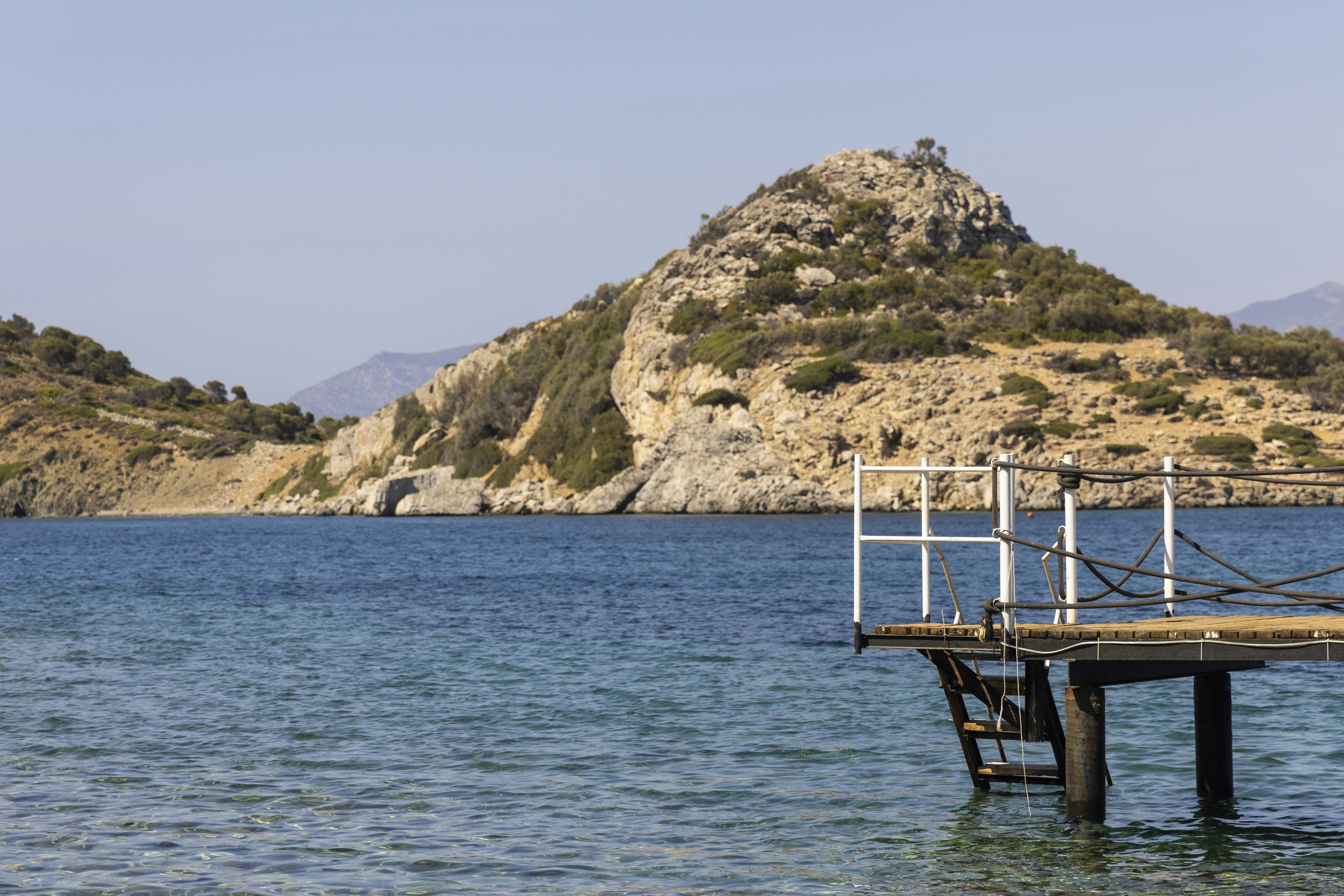Dockside Gaze: A Stone Island Rising from Quiet Blue Waters