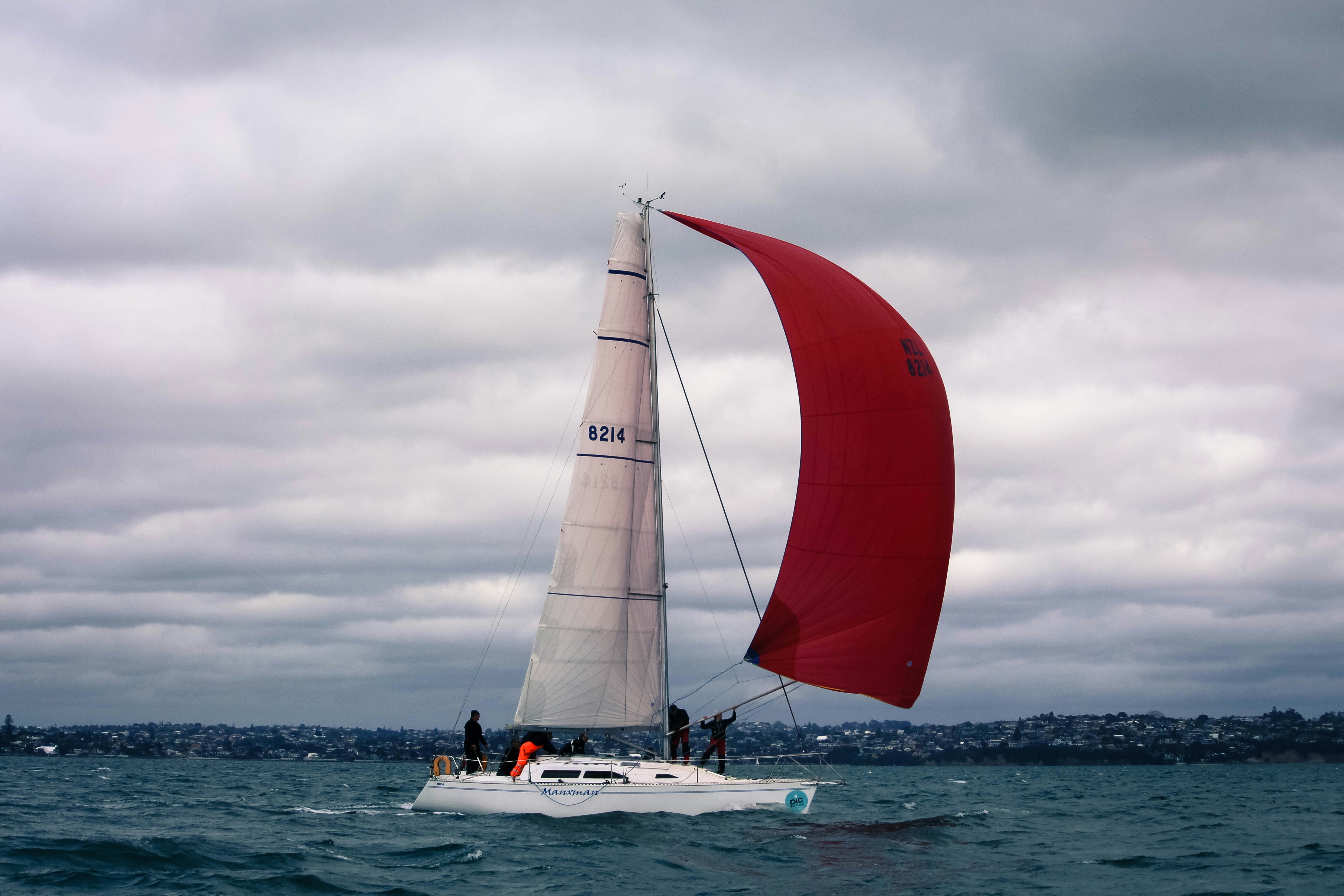 Red sail boat on sea under cloudy sky during daytime photo – Free ...