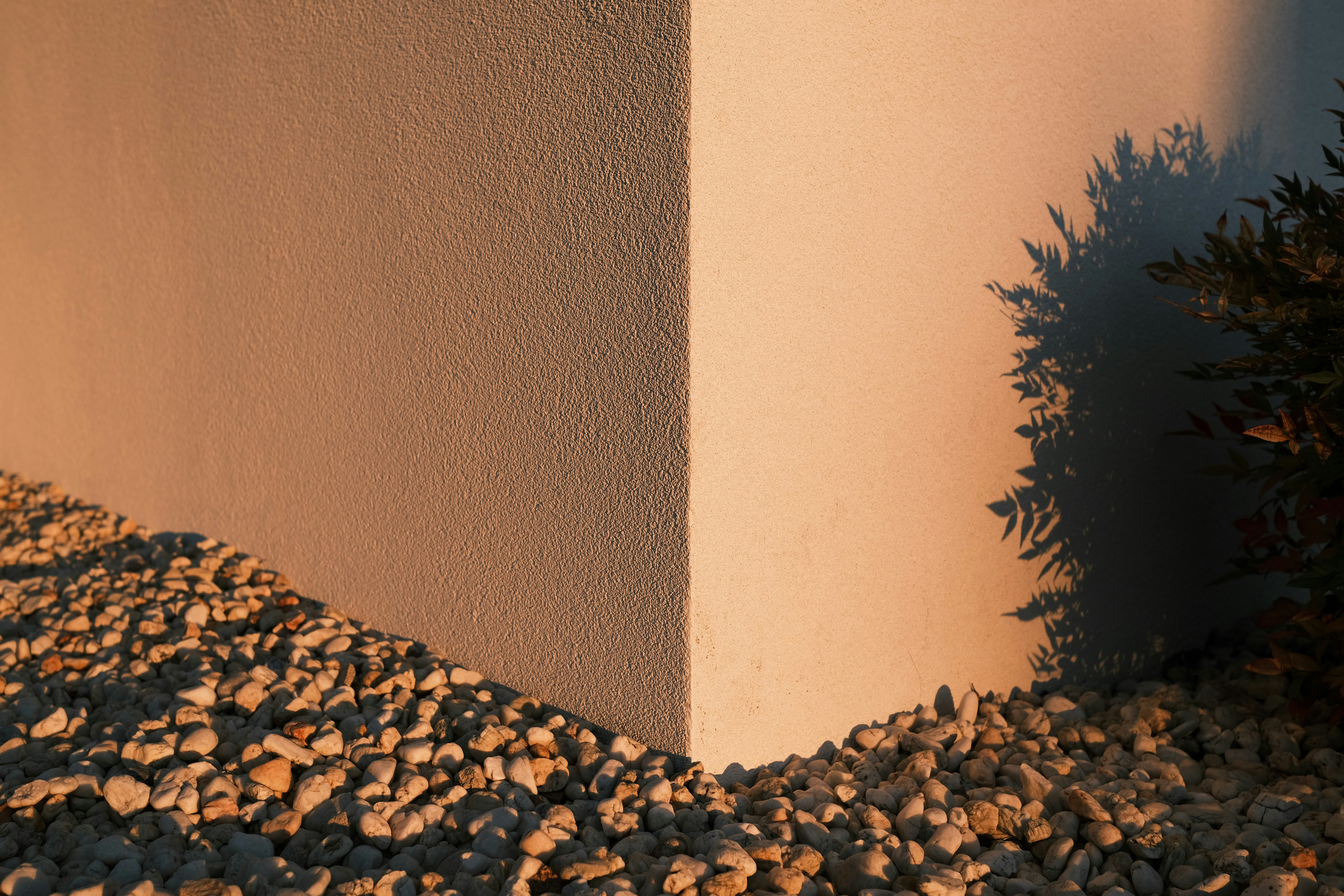 Sun-Warmed Corner: Pebbles Meet the Quiet Geometry of Stucco