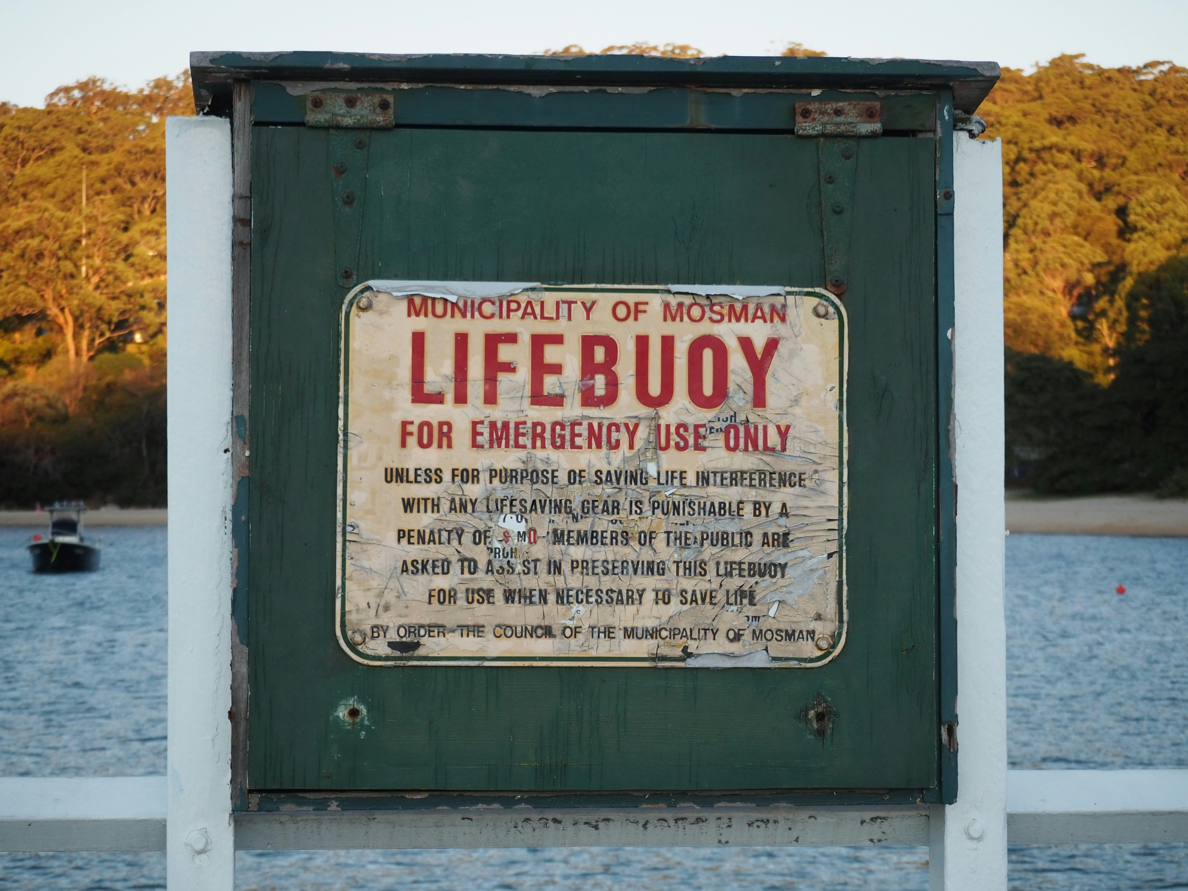 Lifebuoy sign mounted on a wooden structure, conveying important safety information for emergency use at a waterfront location.