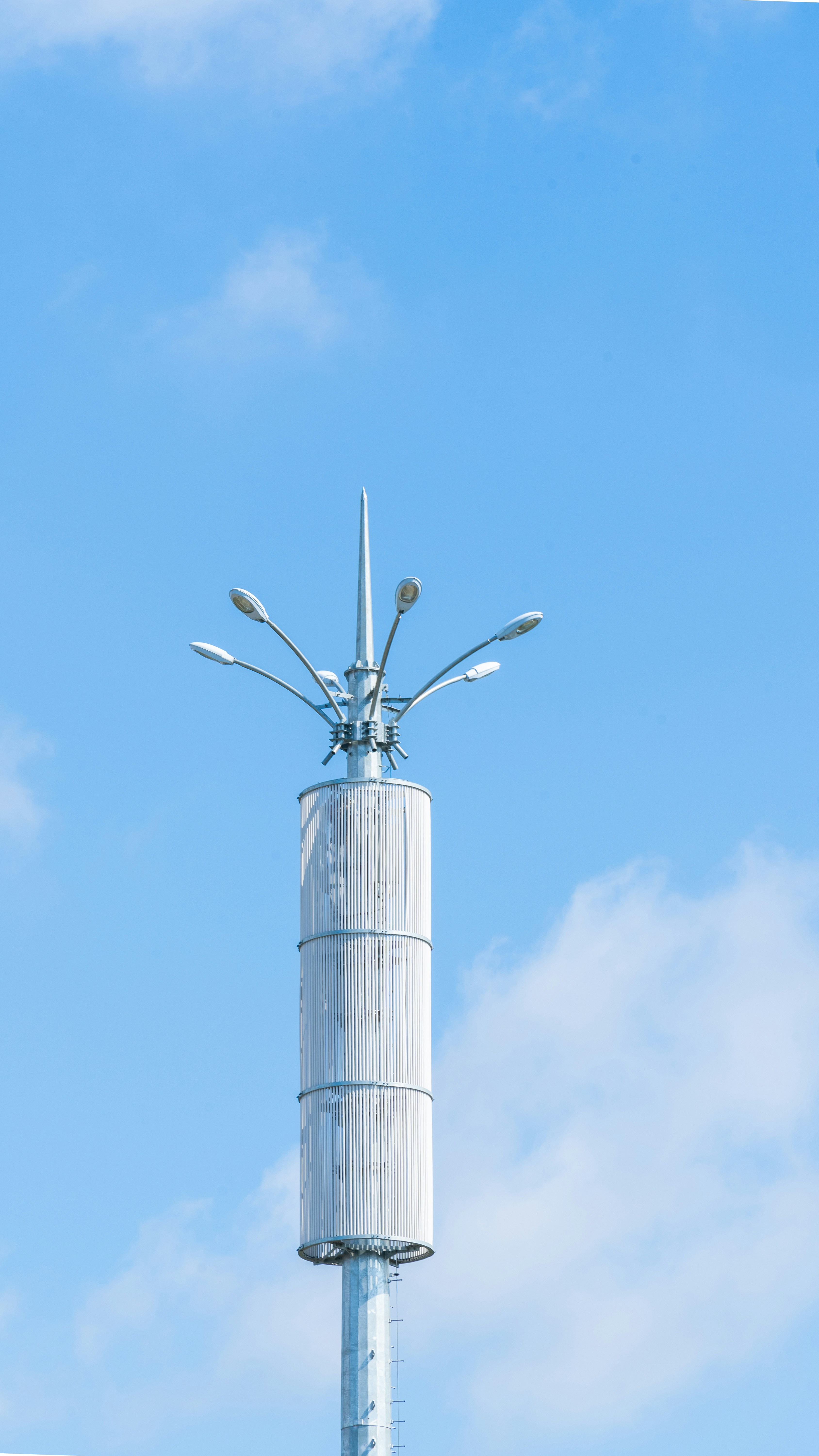 Sleek modern light pole with multiple LED fixtures against a clear blue sky.