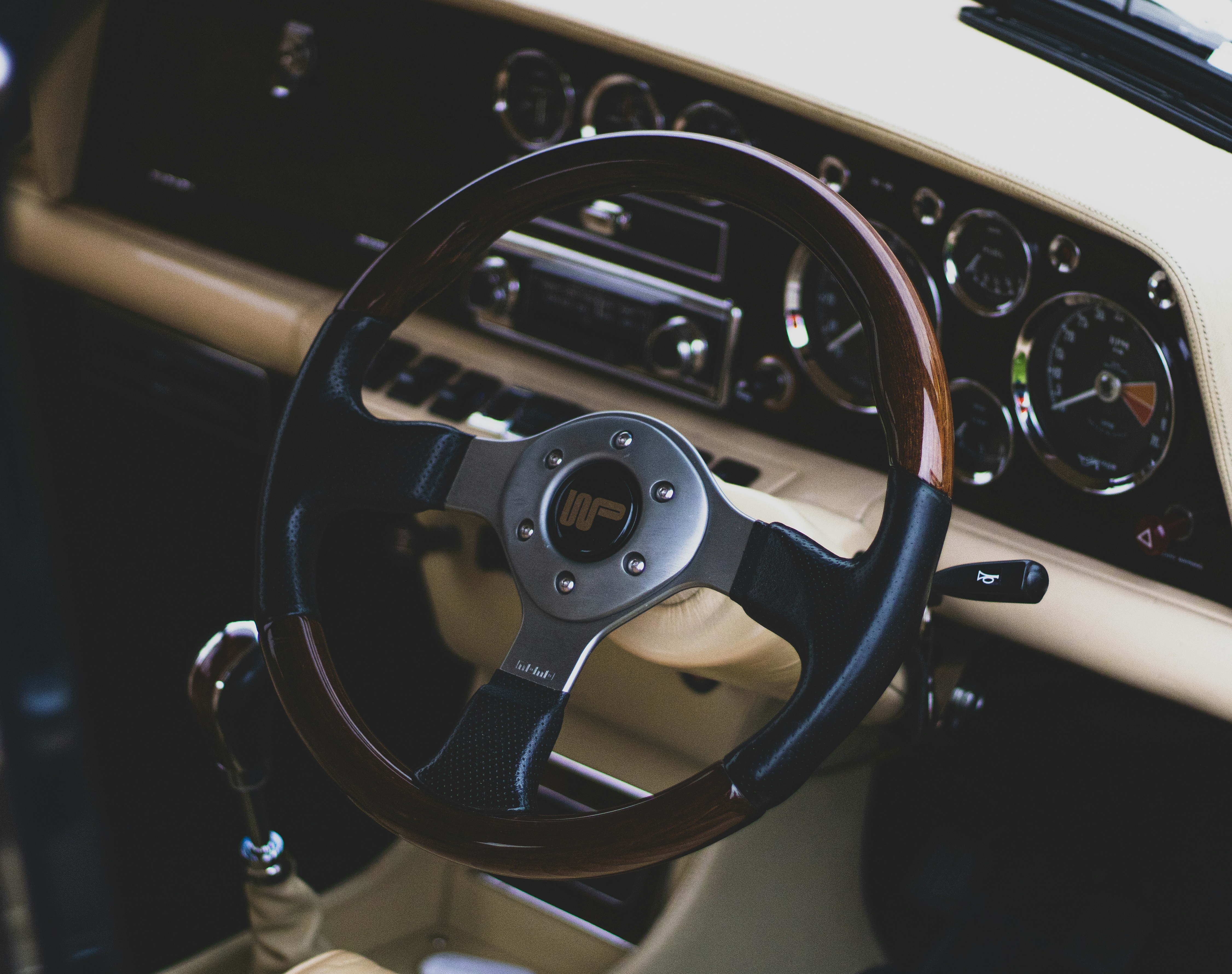 Classic car steering wheel with a polished wooden rim and sleek dashboard details, showcasing vintage automotive design elements.