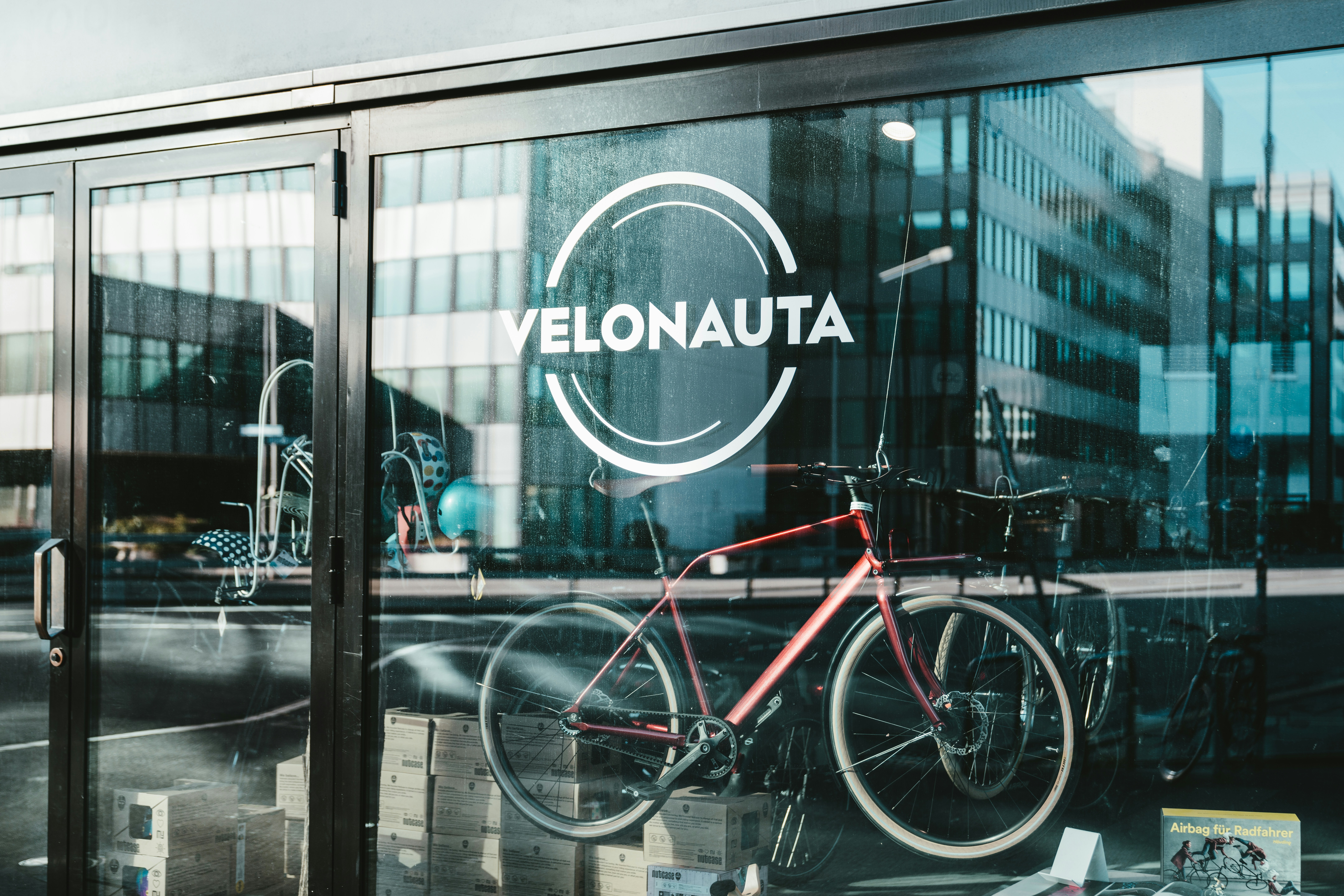 Red and black road bike parked beside glass window photo – Free Zurich ...