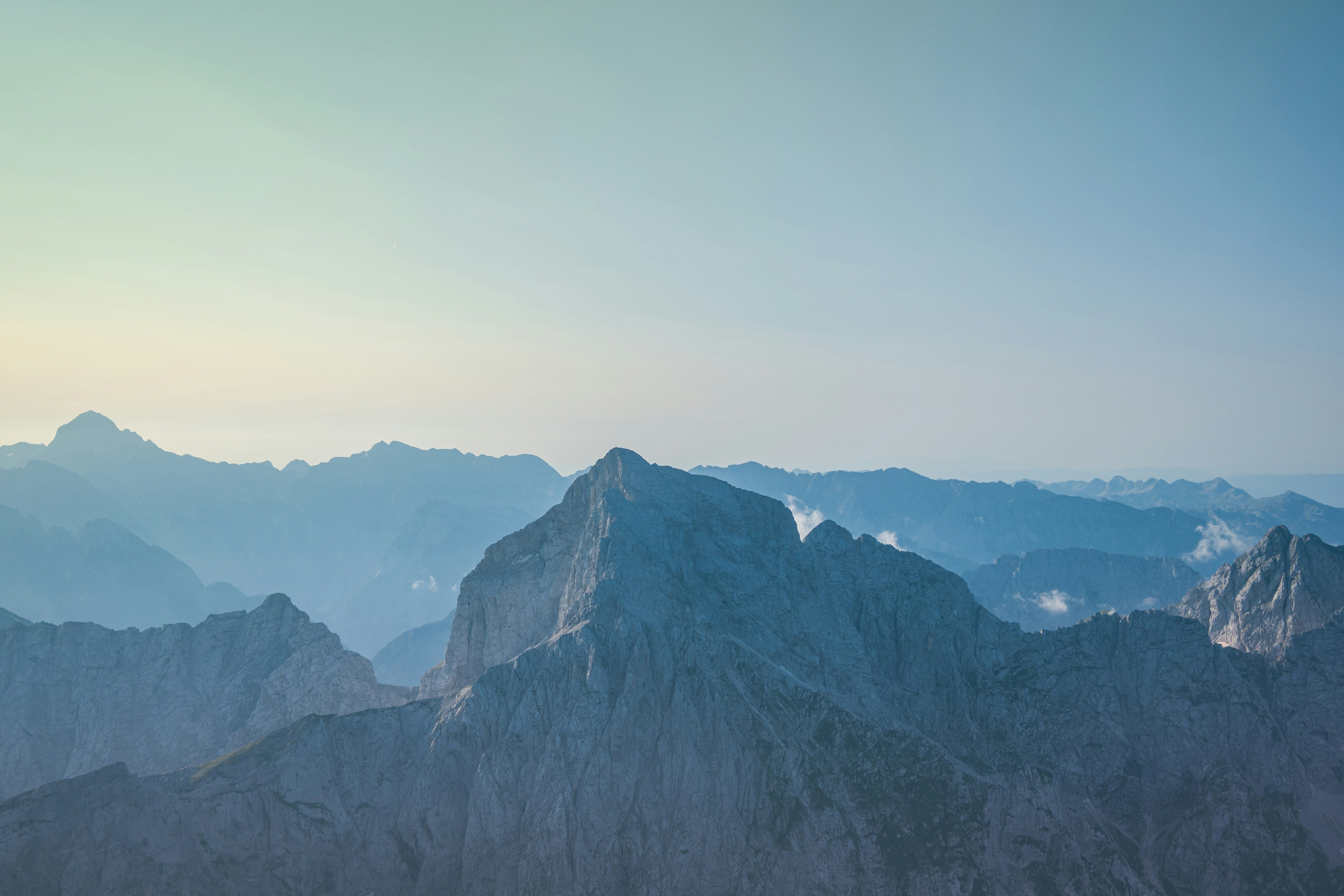 Mountain range silhouettes under a soft gradient sky during daytime.