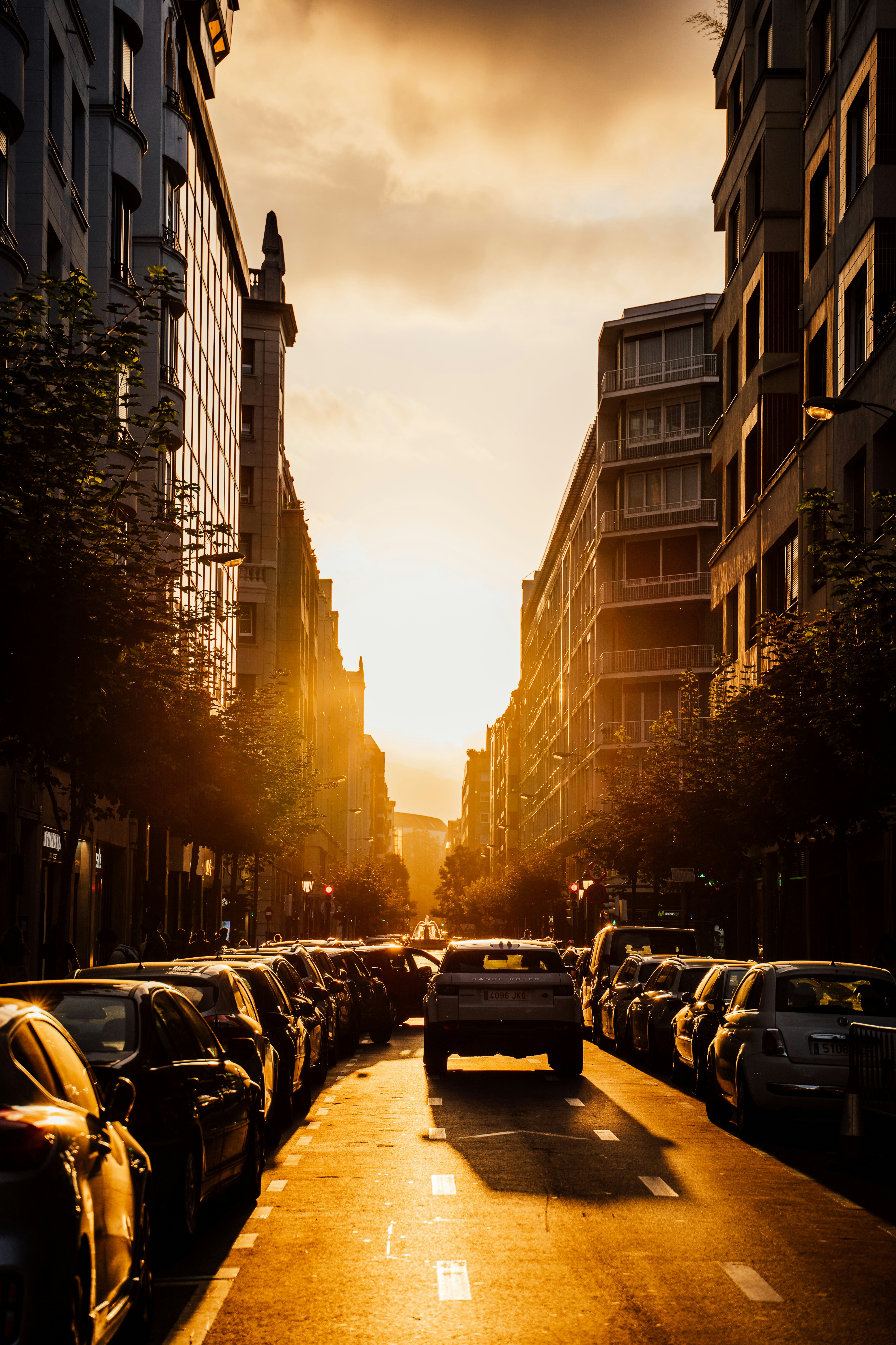 Cars parked on side of the road in between high rise buildings during ...