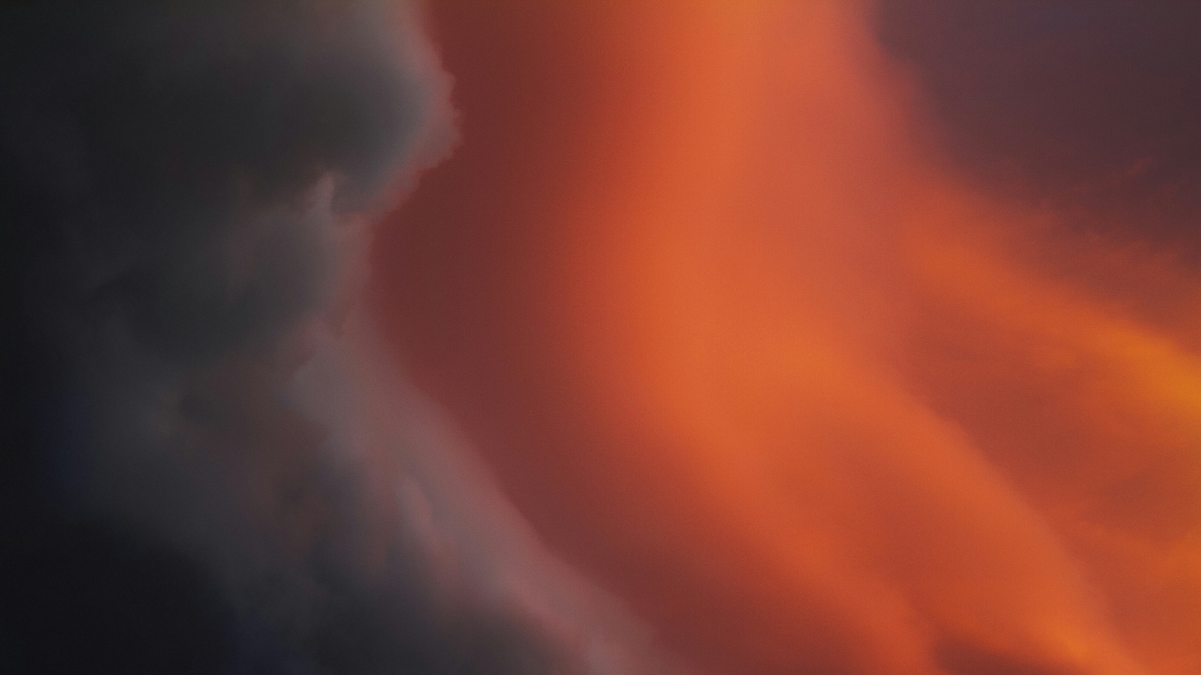 Vibrant hues of orange and deep gray swirl together, creating a dramatic sky at dawn.