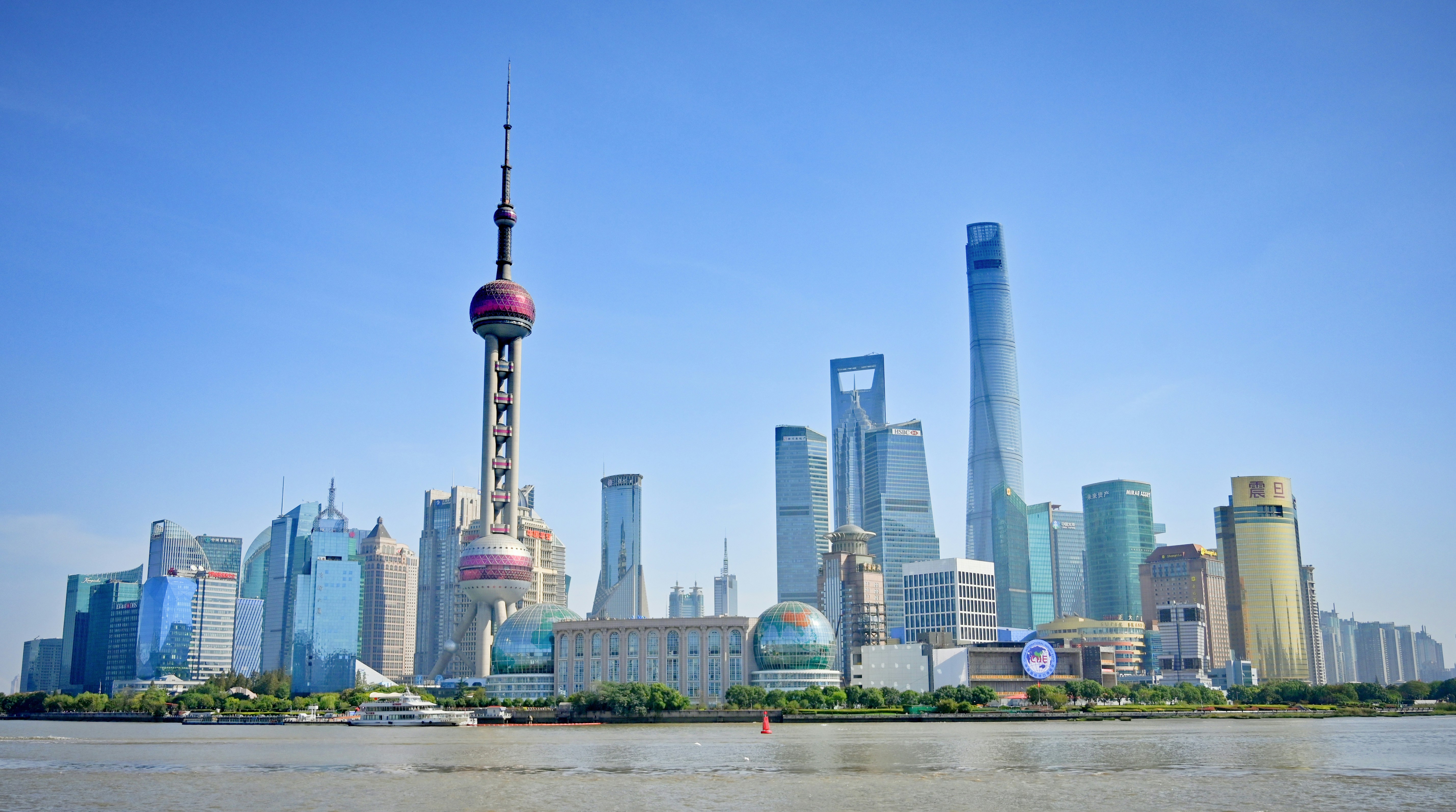 Modern skyscrapers of Shanghai set against a clear blue sky, with the Oriental Pearl Tower prominently featured.