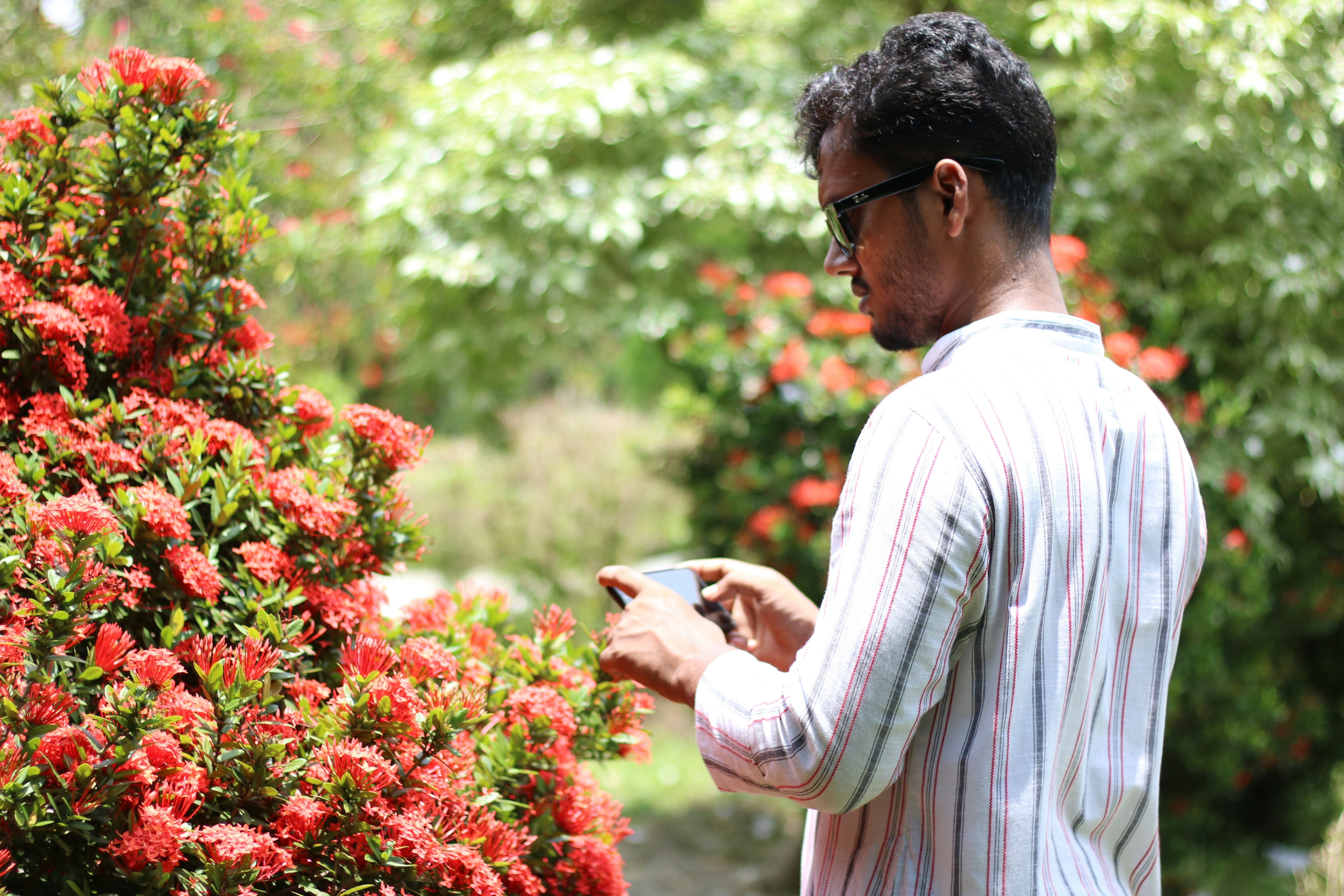 man in white and brown stripe dress shirt holding smartphone
