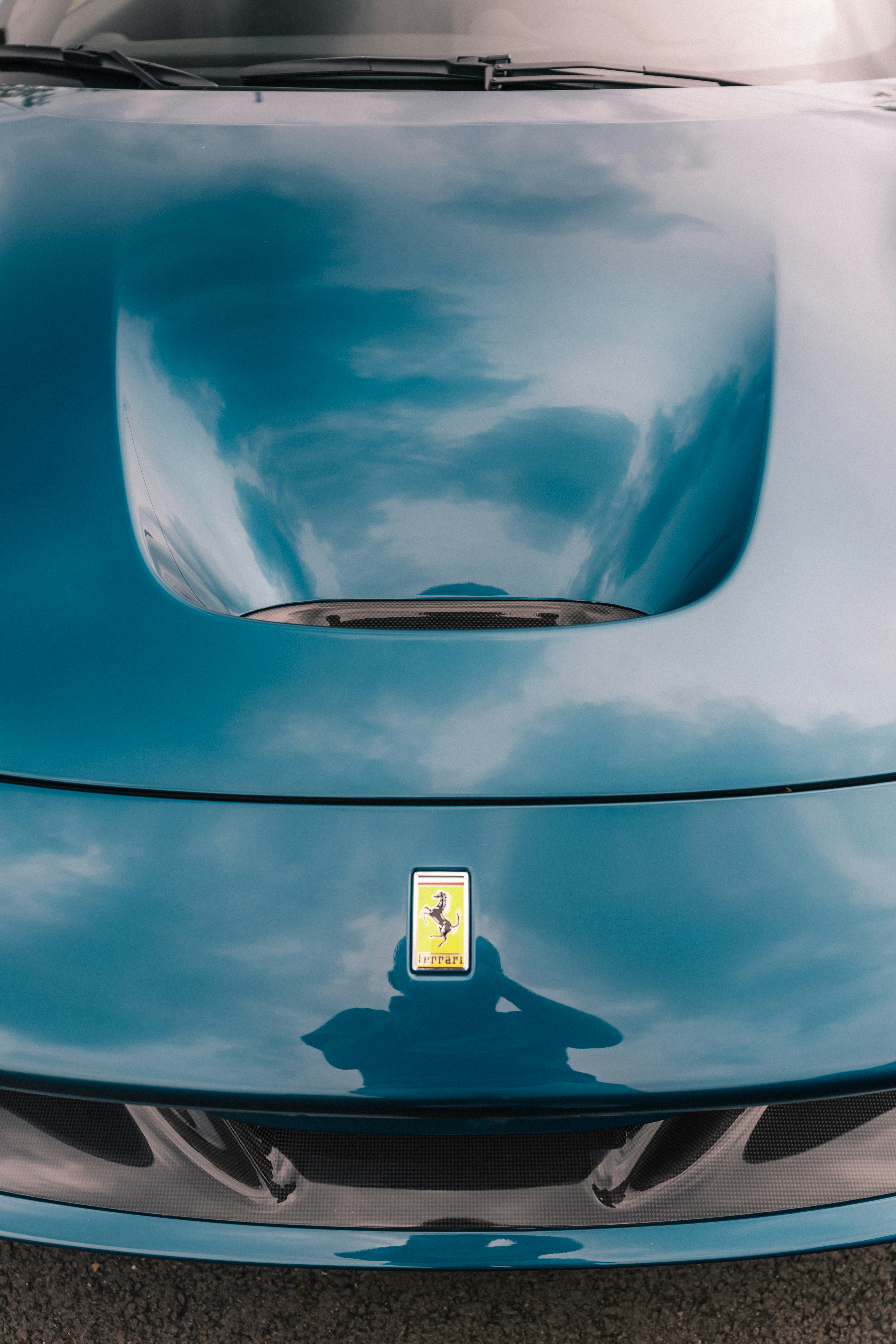 Azure Hood Reflections: The Ferrari Emblem Framed by a Sculpted Intake