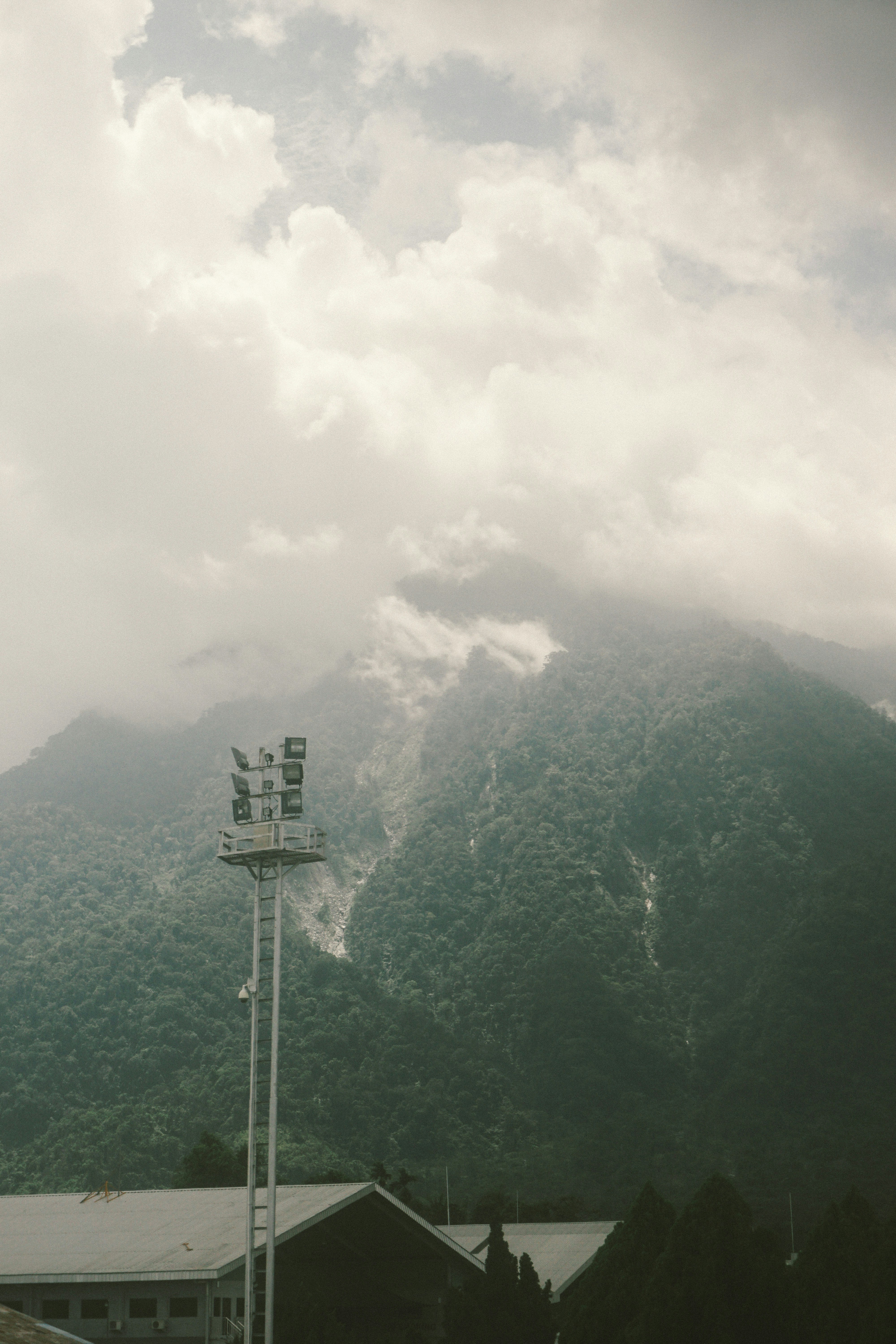 Lone Floodlight Against Misty Alpine Slopes