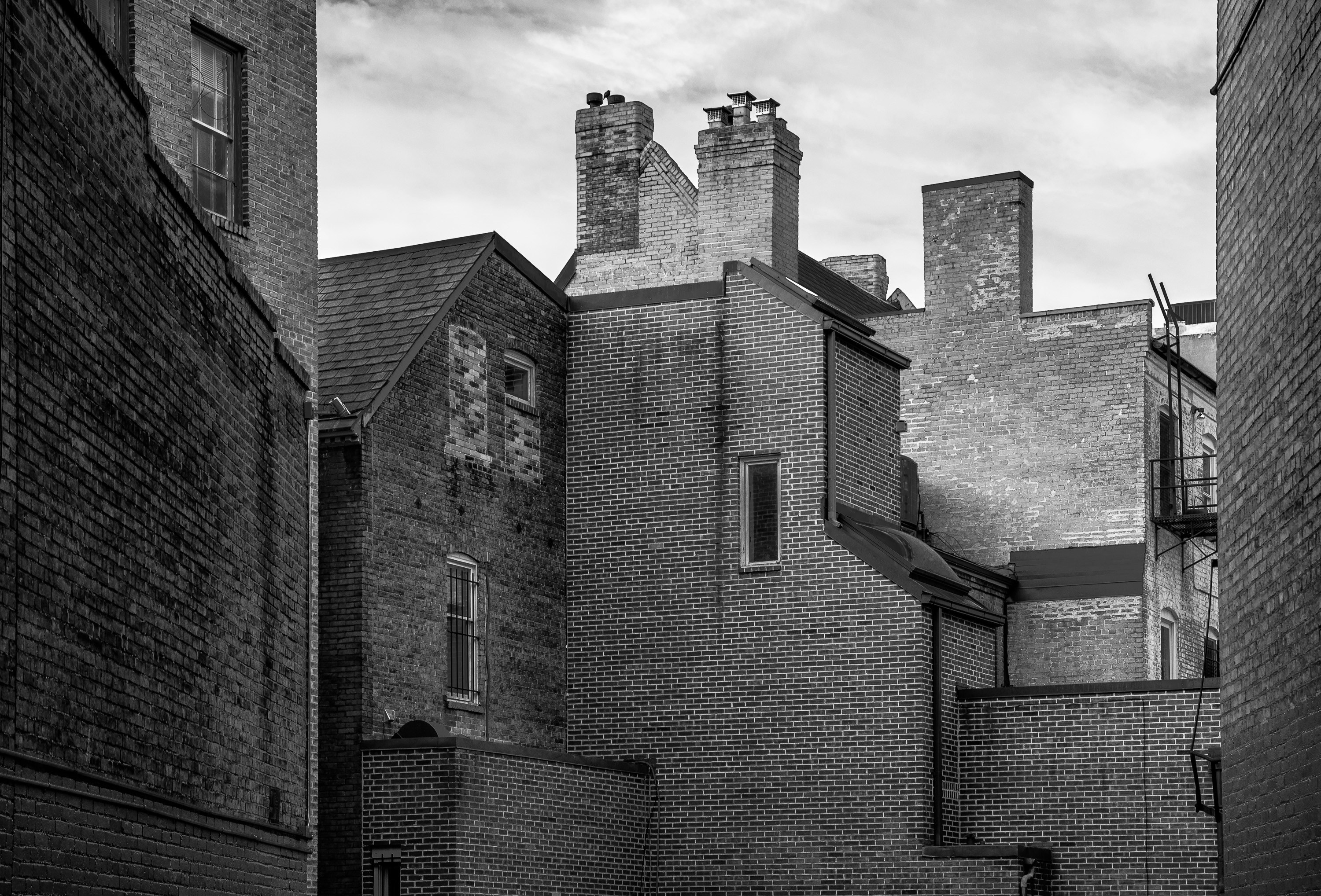 Monochrome view of brick buildings forming a labyrinthine structure, emphasizing the interplay of light and shadow.