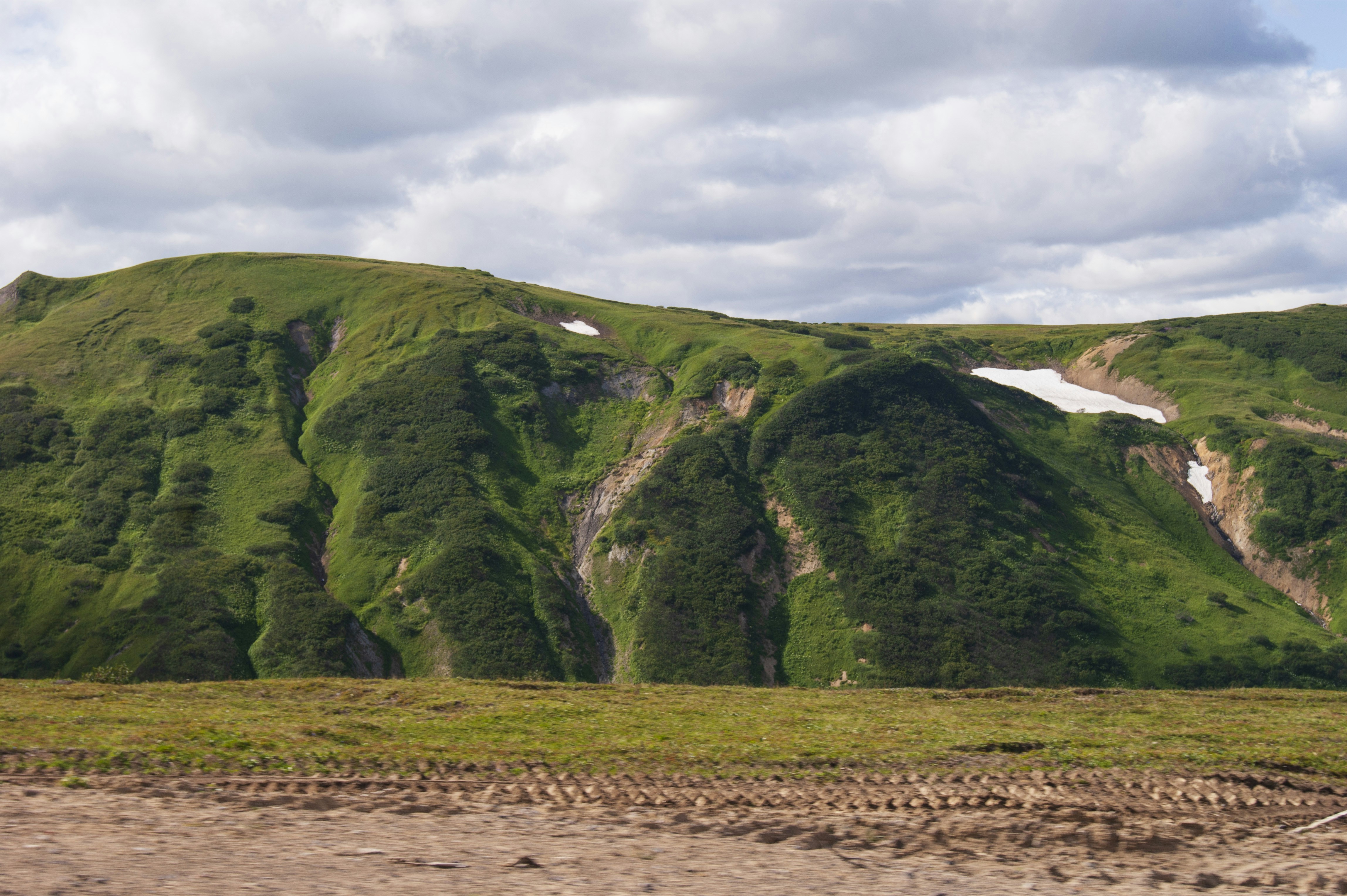 Verdant Peaks Under Billowing Clouds