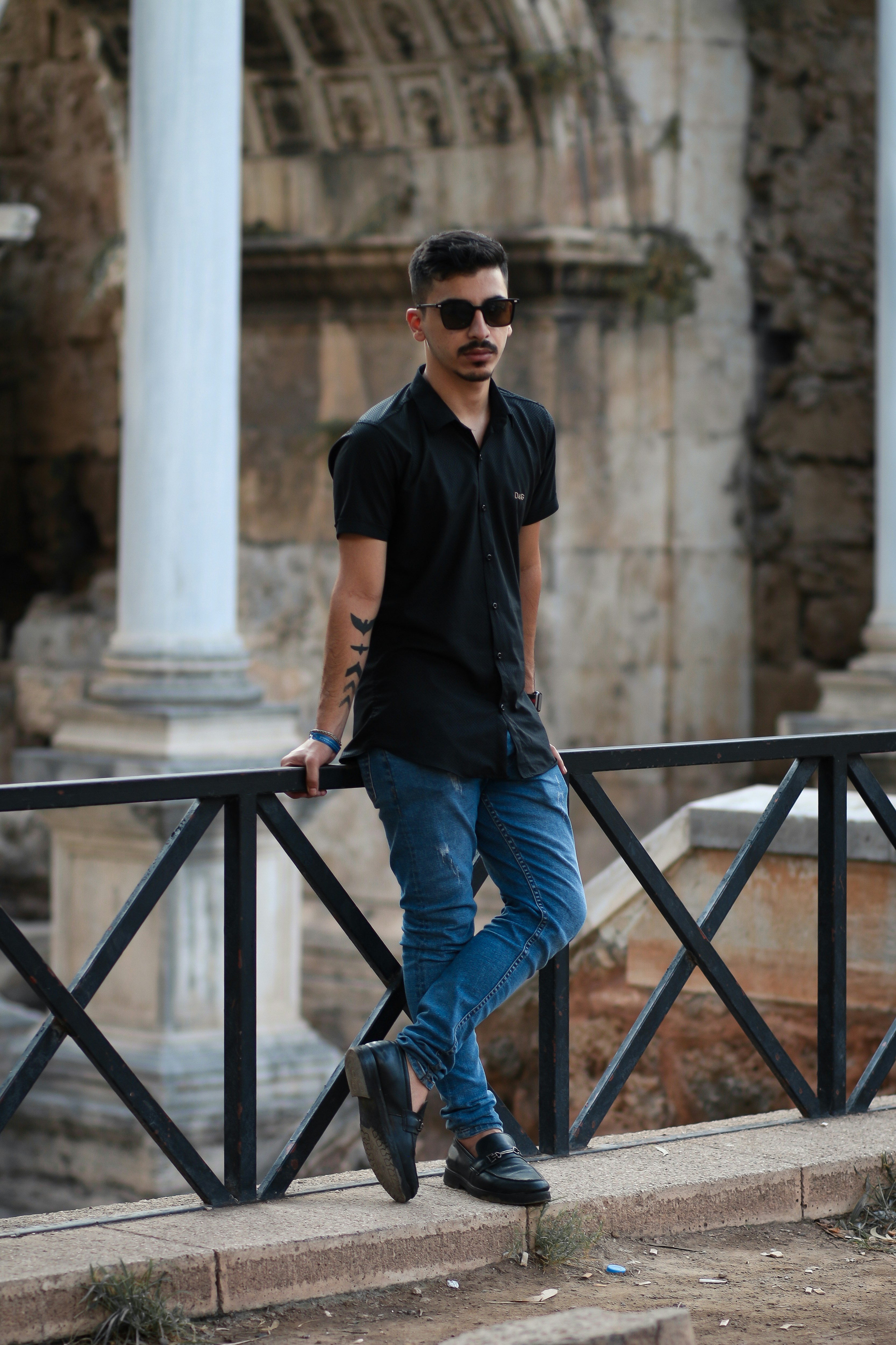 man in black crew neck t-shirt and blue denim jeans standing on gray concrete stairs