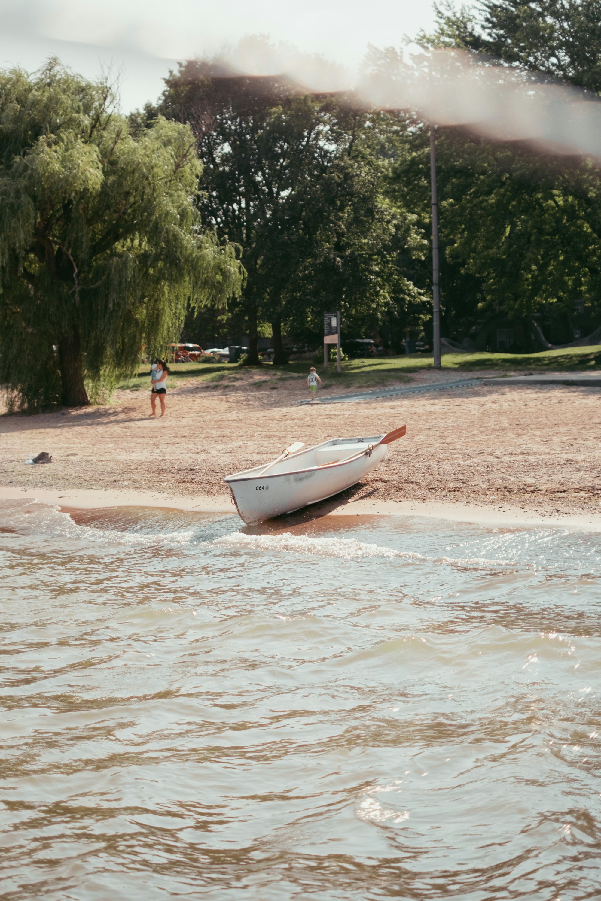 White Rowboat at the Lakeshore: A Quiet Moment Among Green Canopy