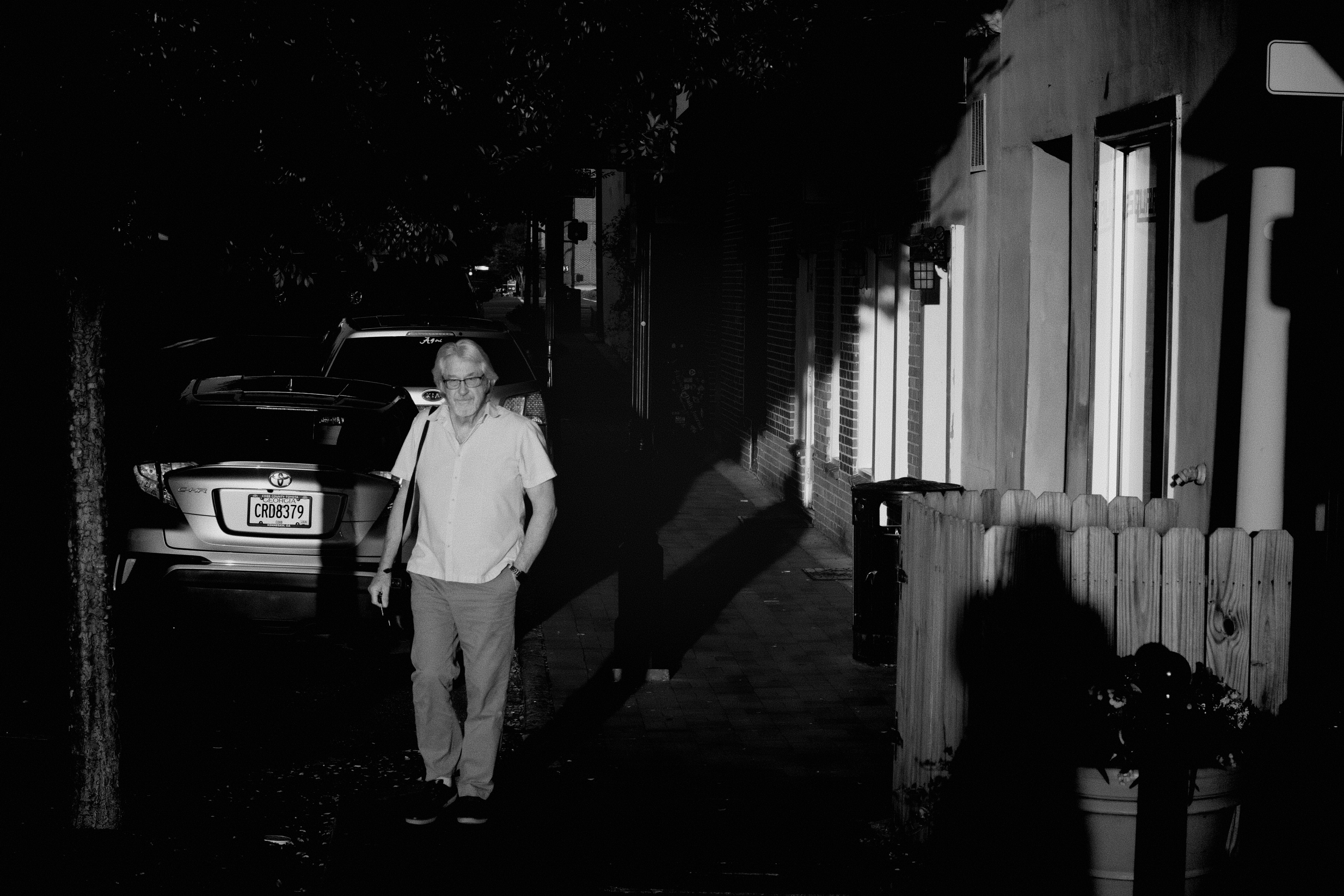Man in white dress shirt and black pants standing beside white building ...