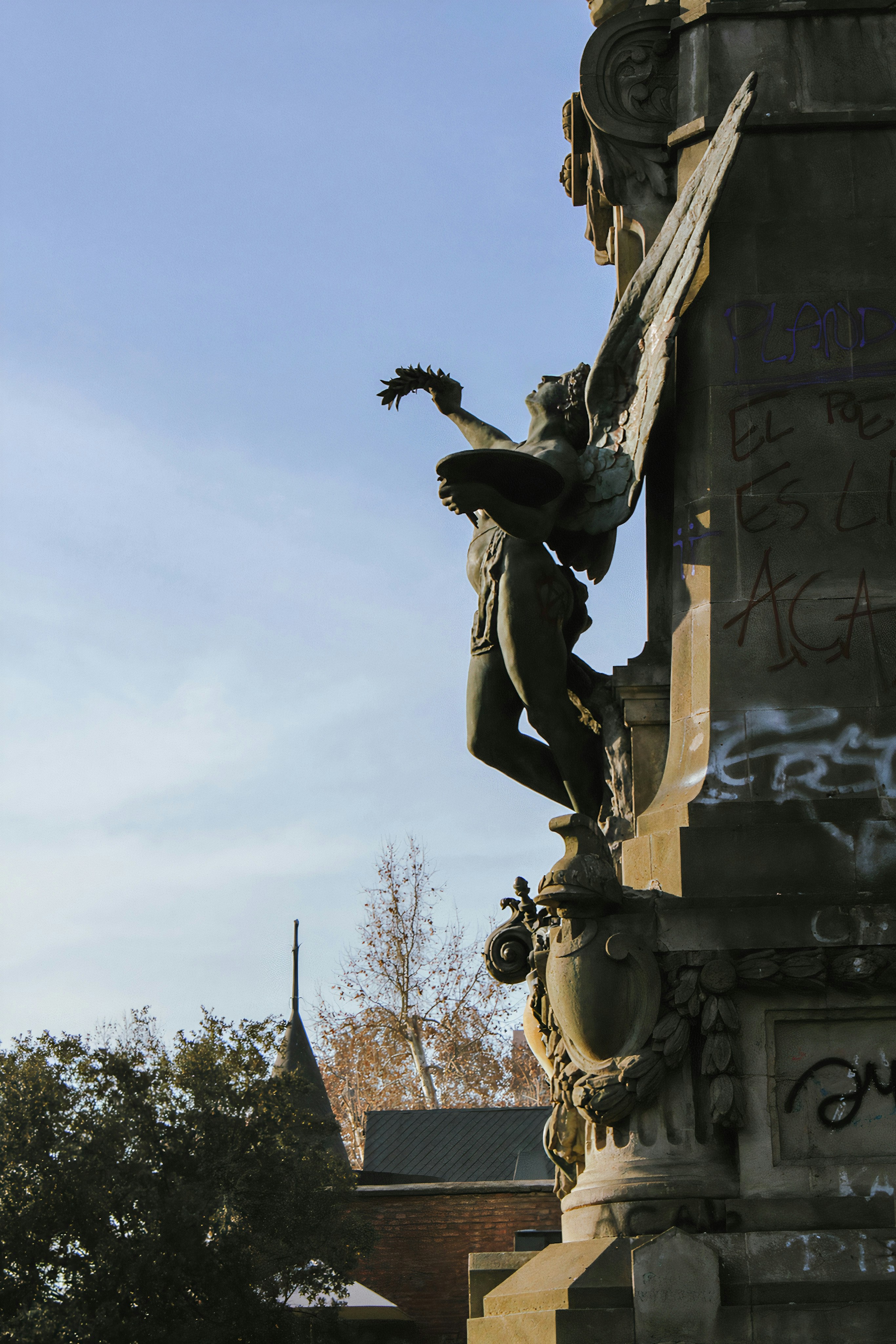 Winged Sentinel Over a Graffiti-Laced Monument Under a Clear Sky