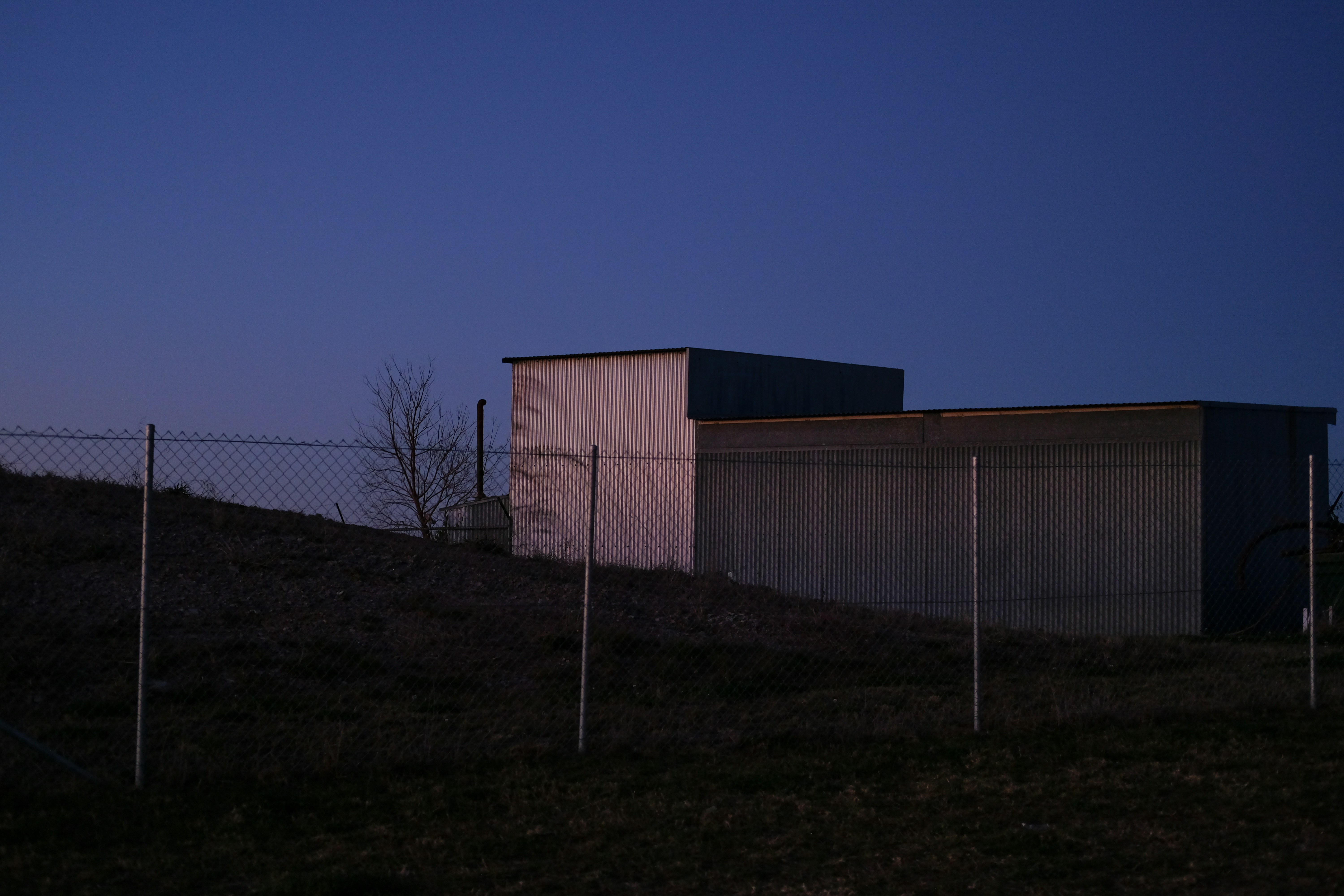Moonlit Outpost Beyond the Chain-Link Fence