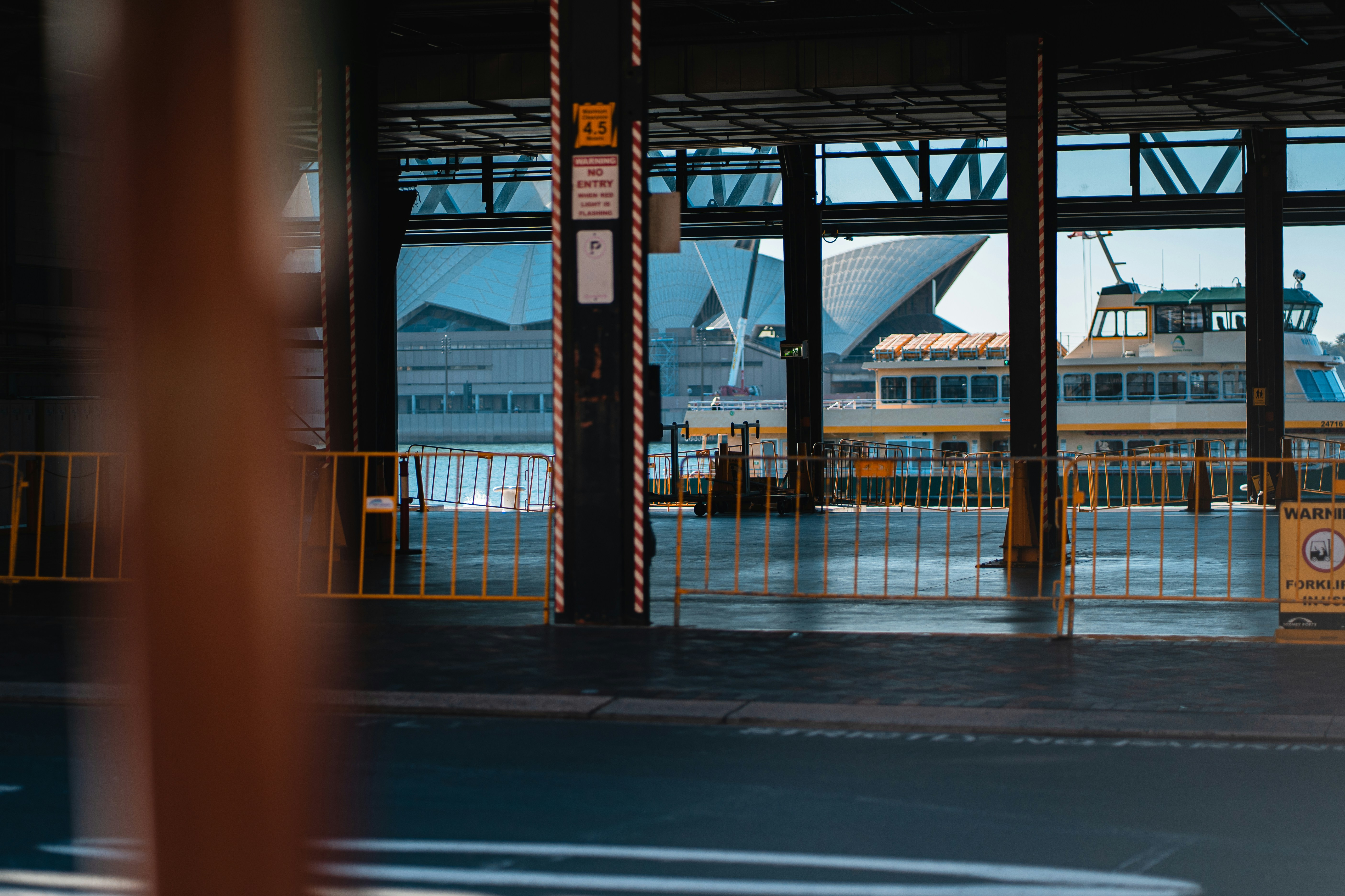 Ferry terminal framed by industrial architecture, showcasing boats and modern structures in the background.