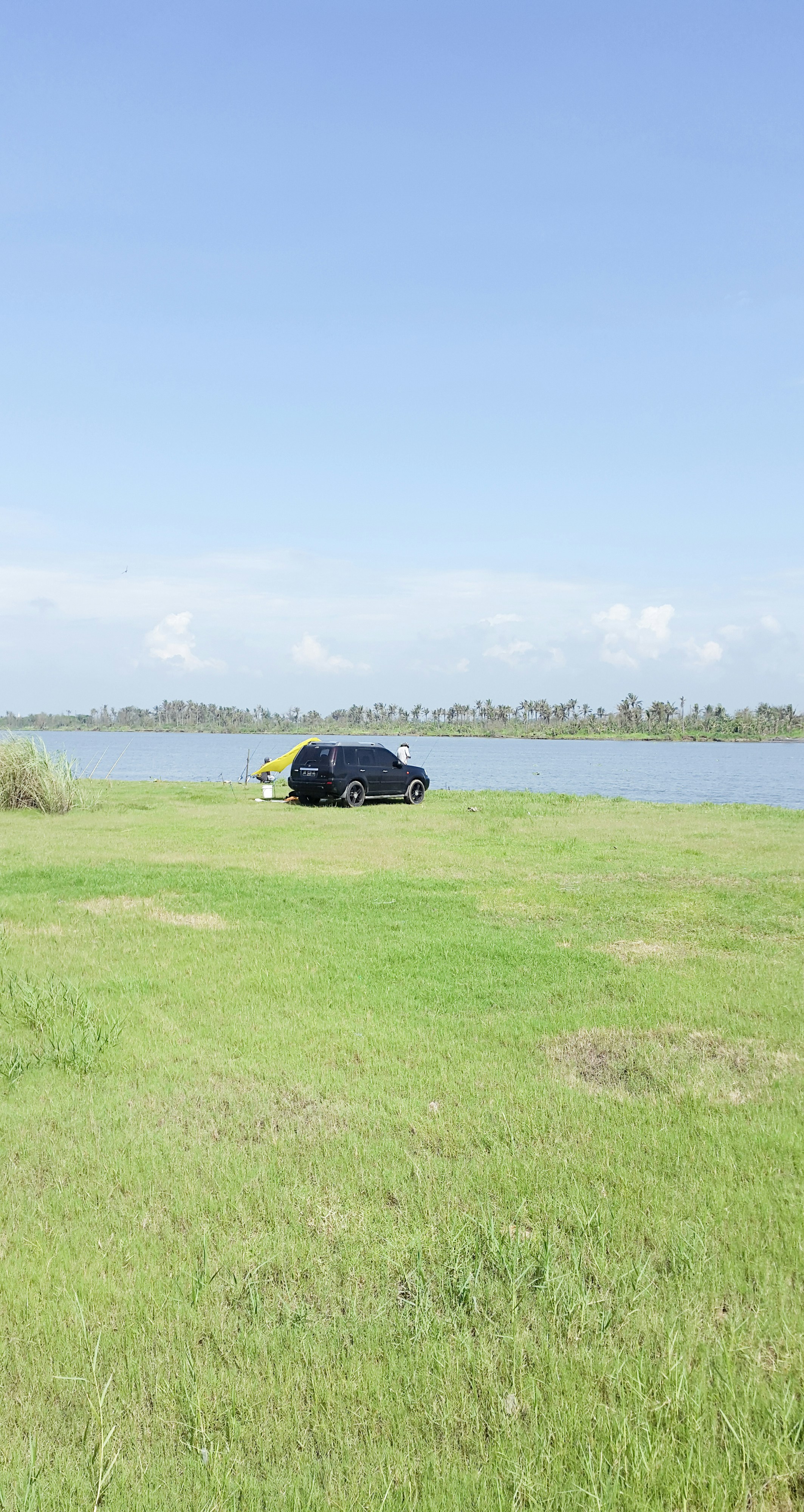 Lakeside Stopover: Black SUV by a Bright Yellow Shade on the Grass